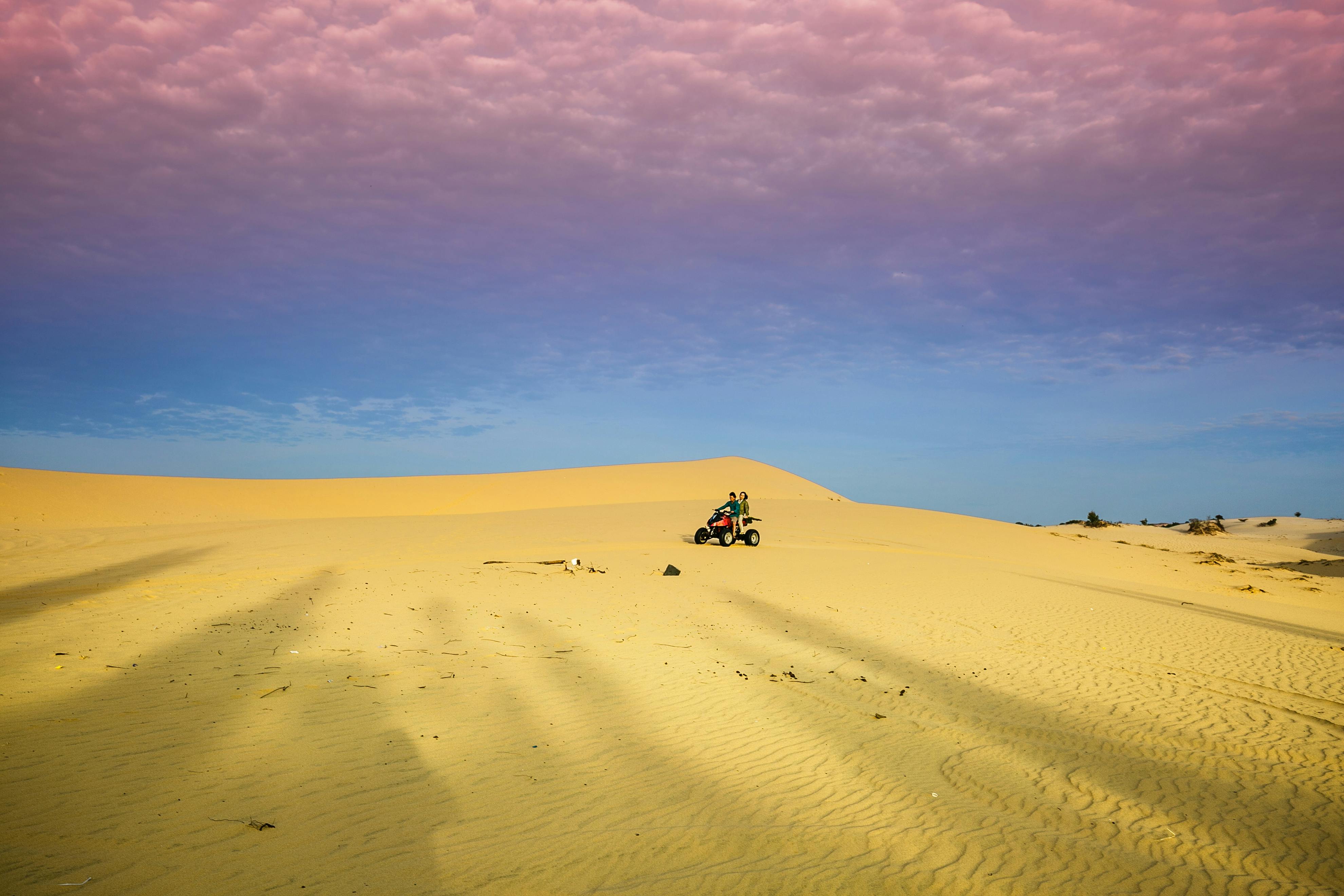 People Riding Quad Bike on Desert Under Blue Sky · Free Stock Photo