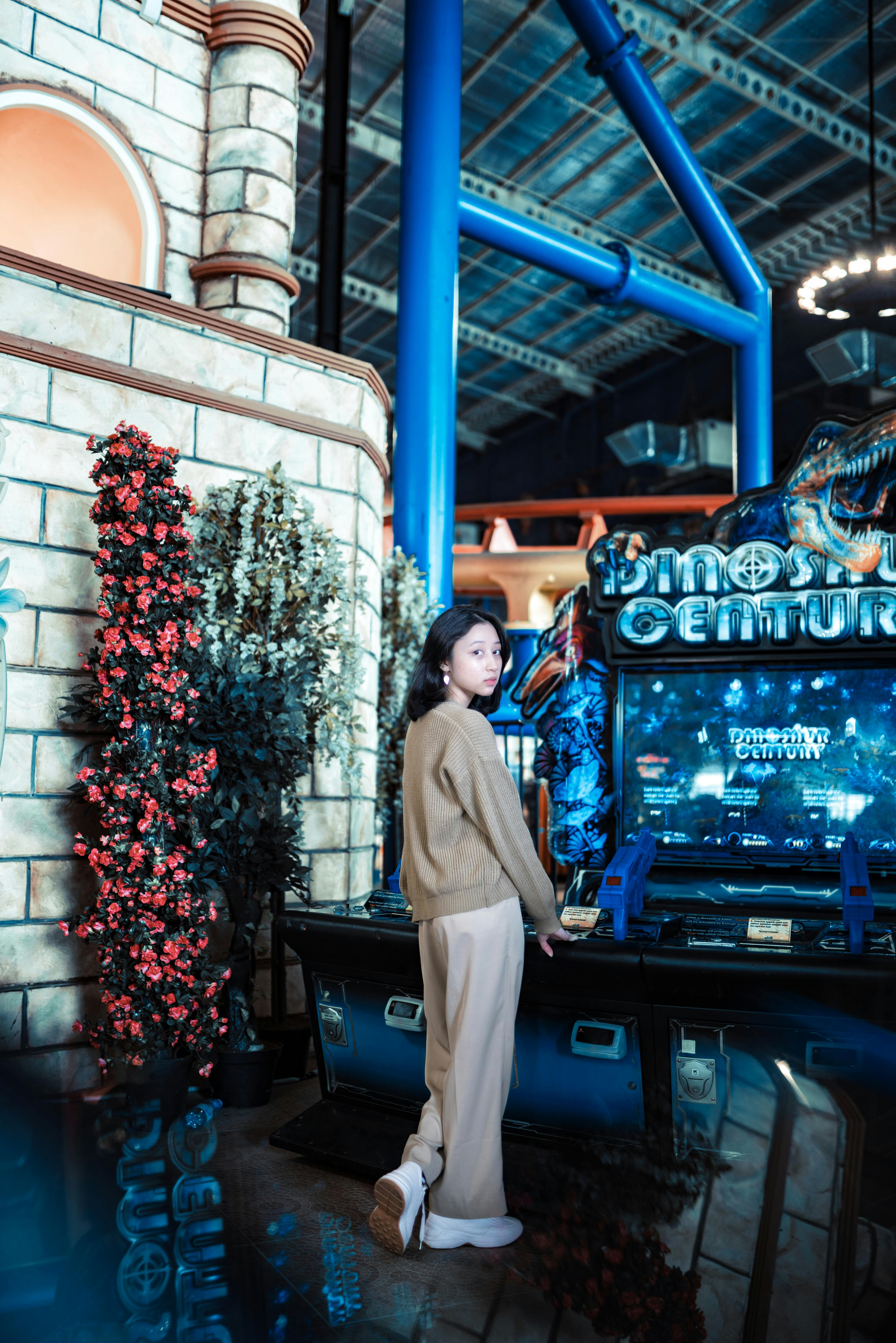 A Woman in Beige Coat Standing Beside the Arcade Machine · Free Stock Photo