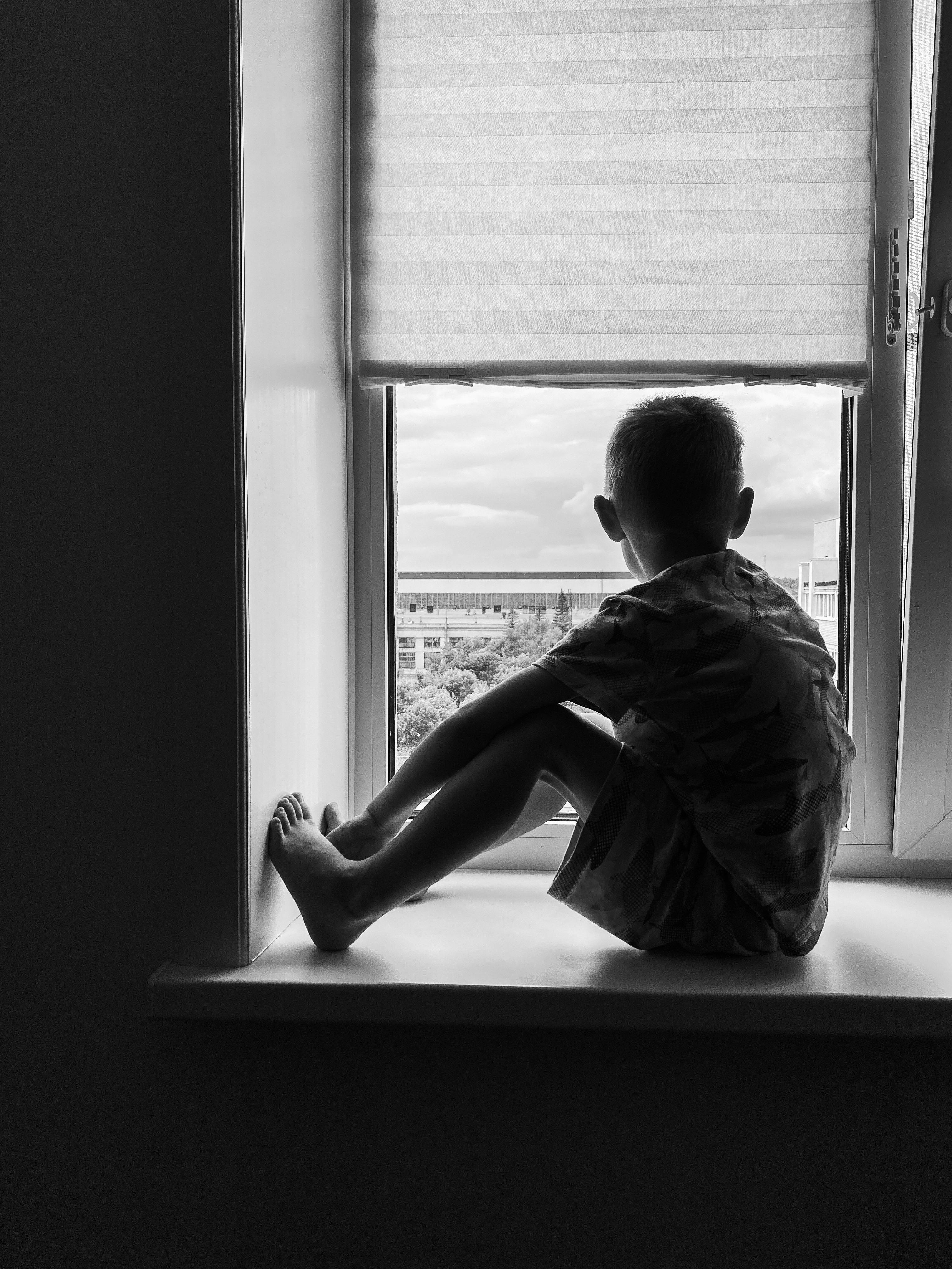 A Grayscale of a Boy Looking Outside the Window · Free Stock Photo