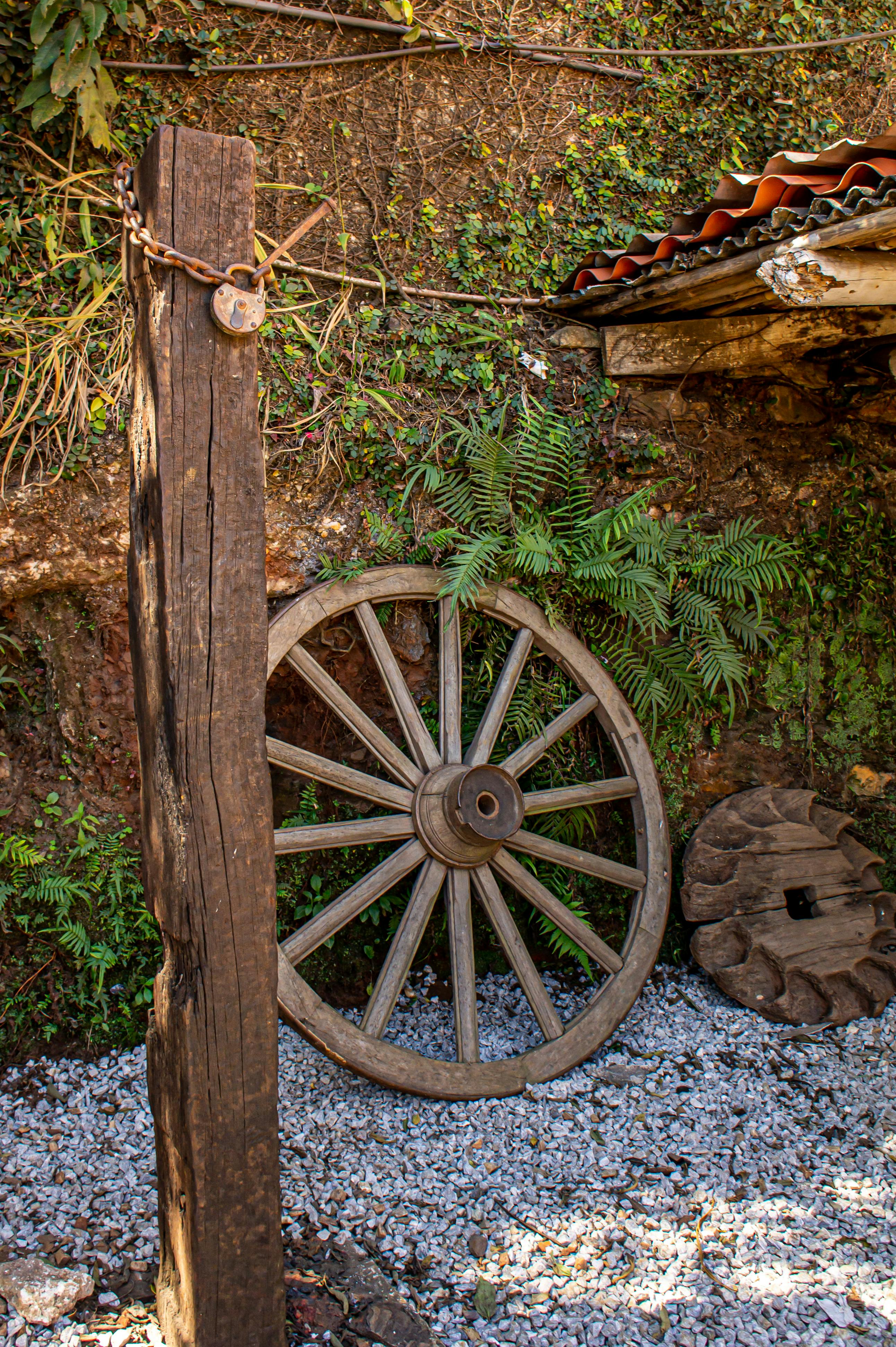 Rustic Wagon Wheel Against Brown Rock · Free Stock Photo