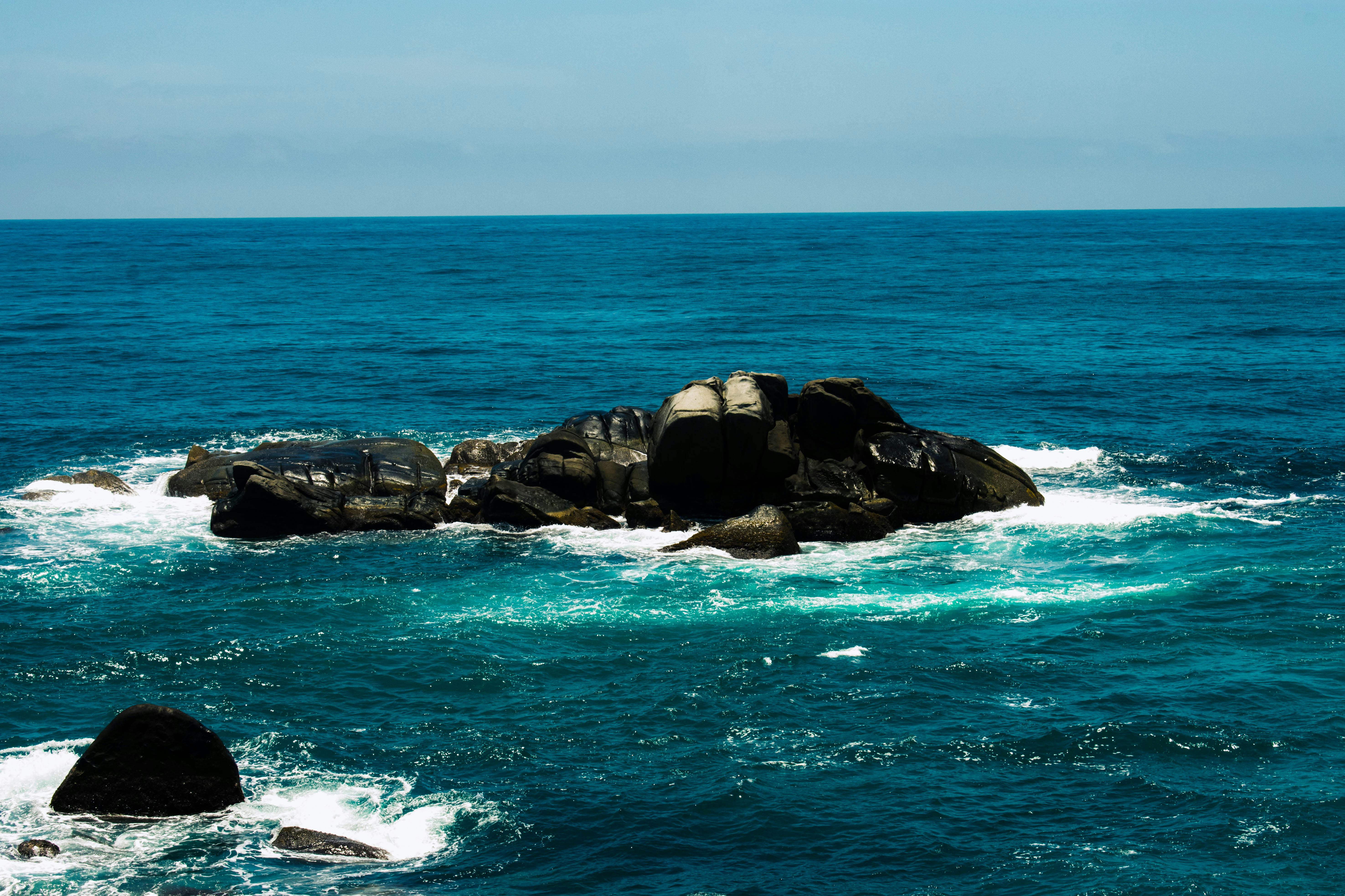 Black Rocks on Blue Body of Water · Free Stock Photo