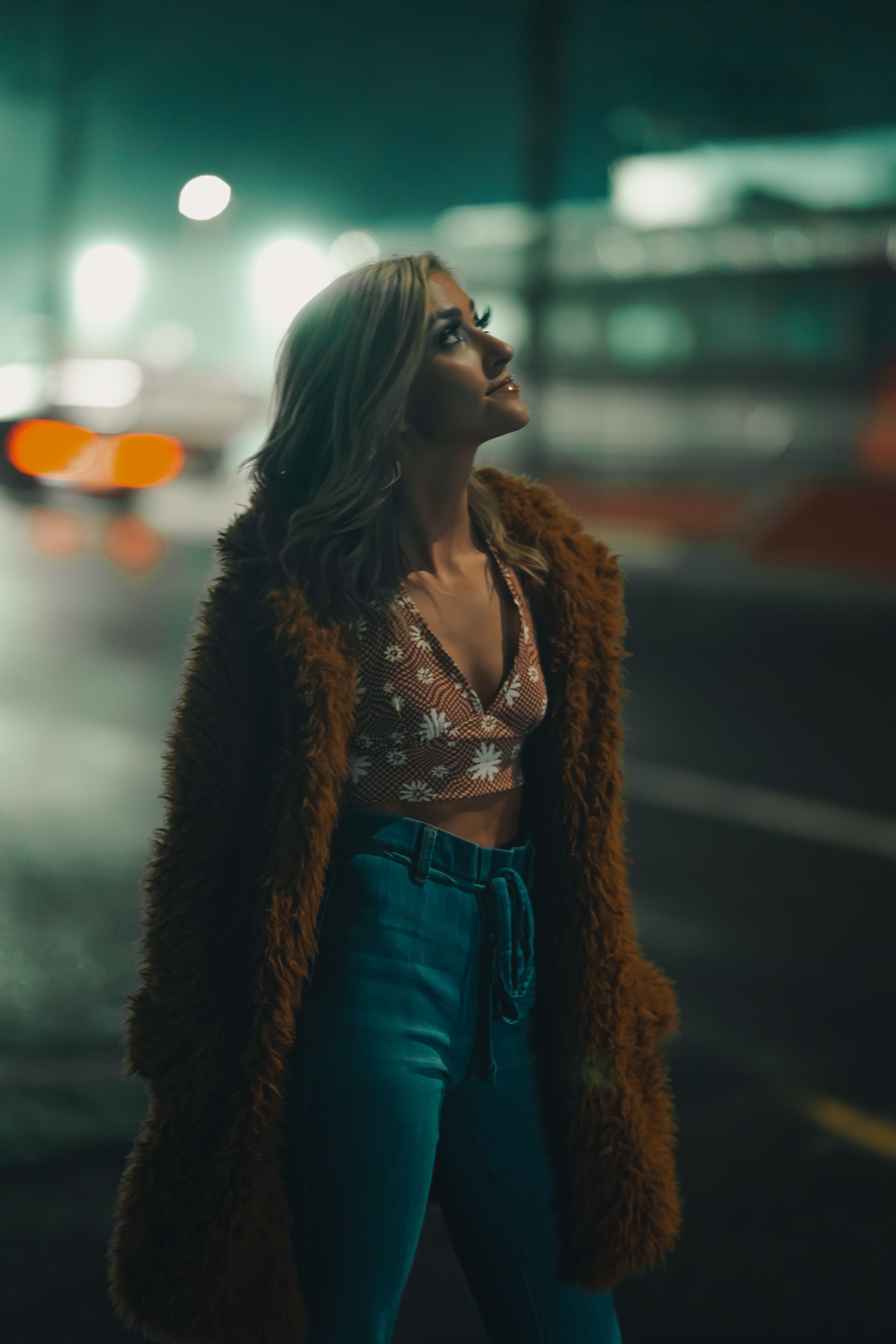 Photo of a Young Woman Standing on a Street Among Street Lamps at Night ...