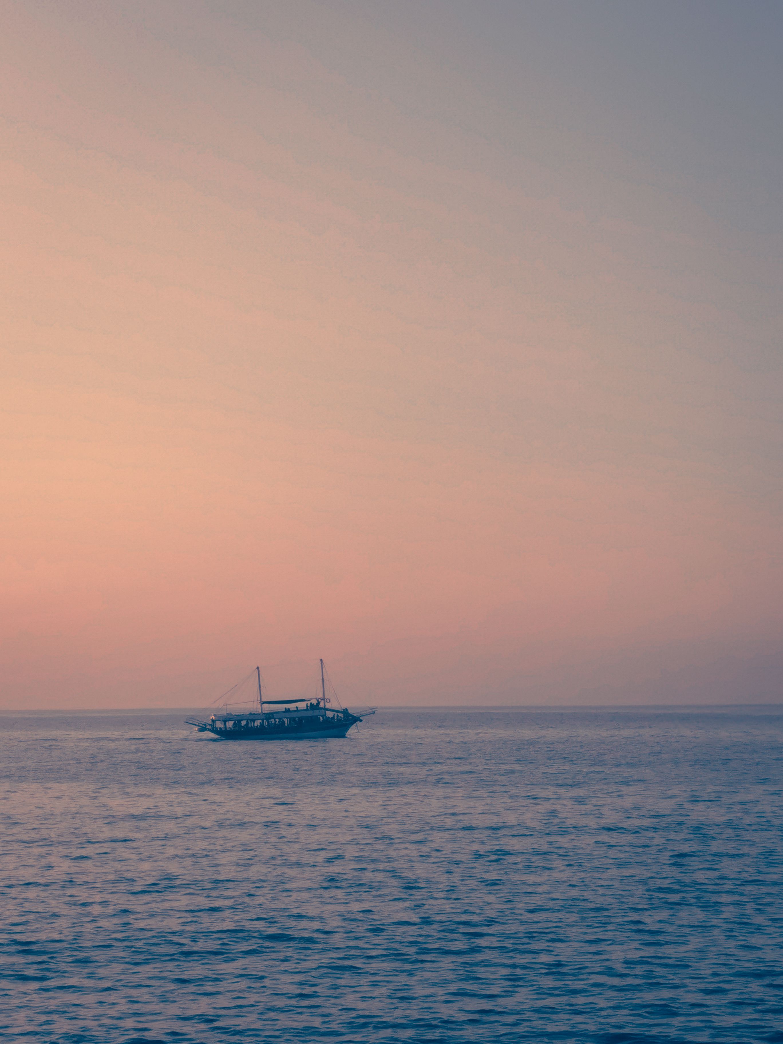 People Sailing in Boat on Horizon in Sea on Sunset · Free Stock Photo