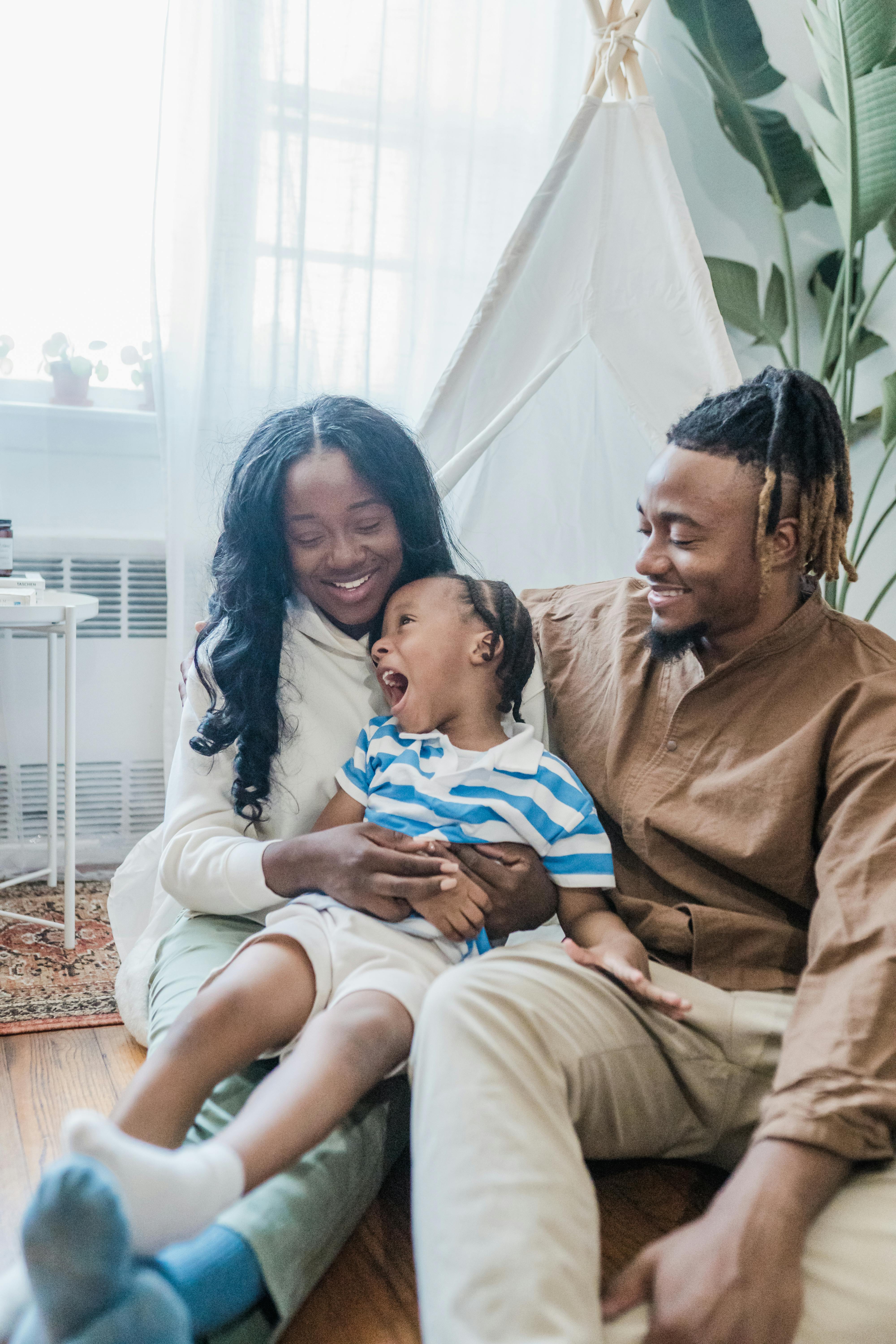 Laughing Boy Sitting on Parents Lap in a Living Room · Free Stock Photo