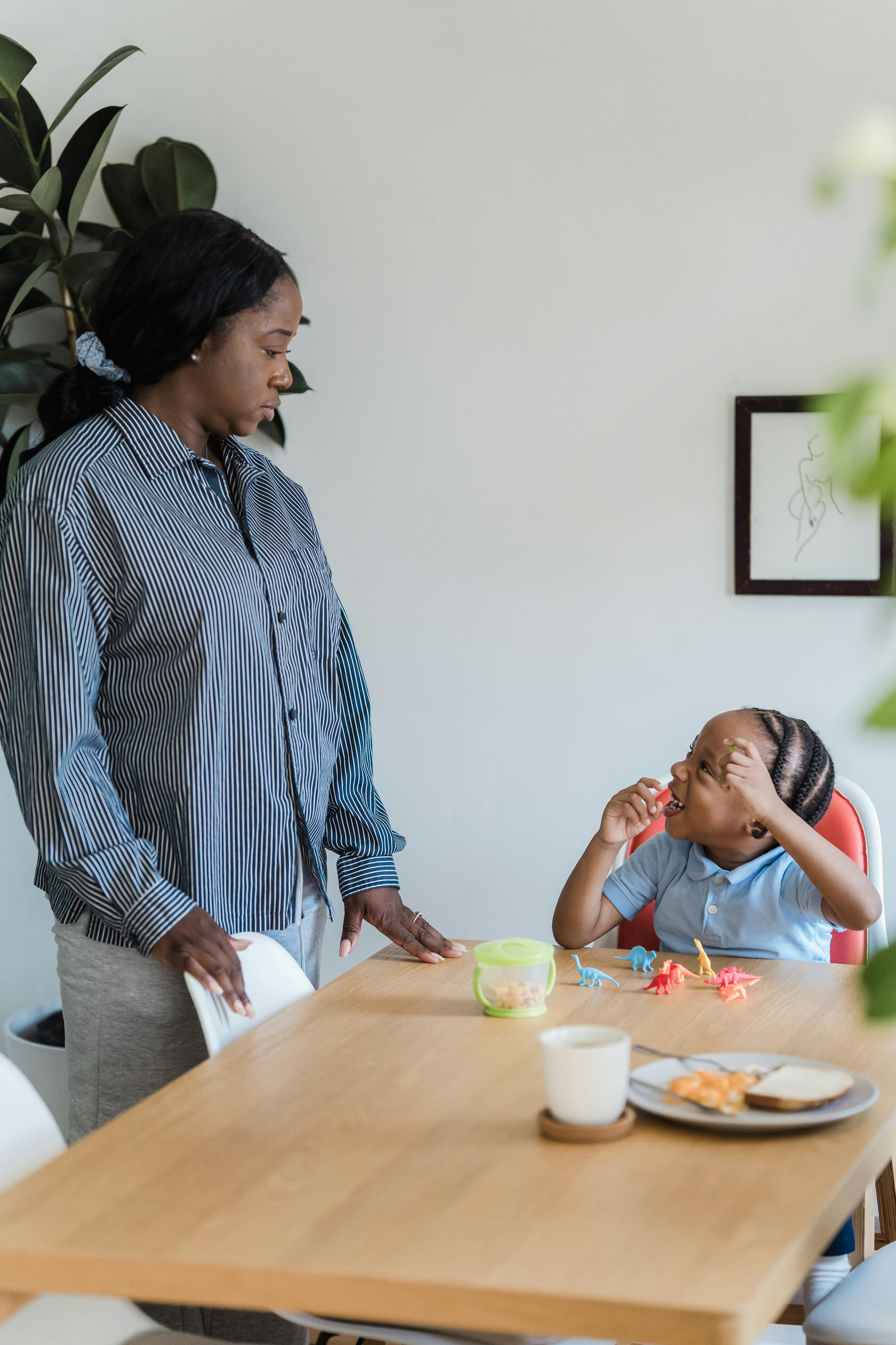 Child Sitting at the Table and Looking and Smiling at his Mother · Free ...