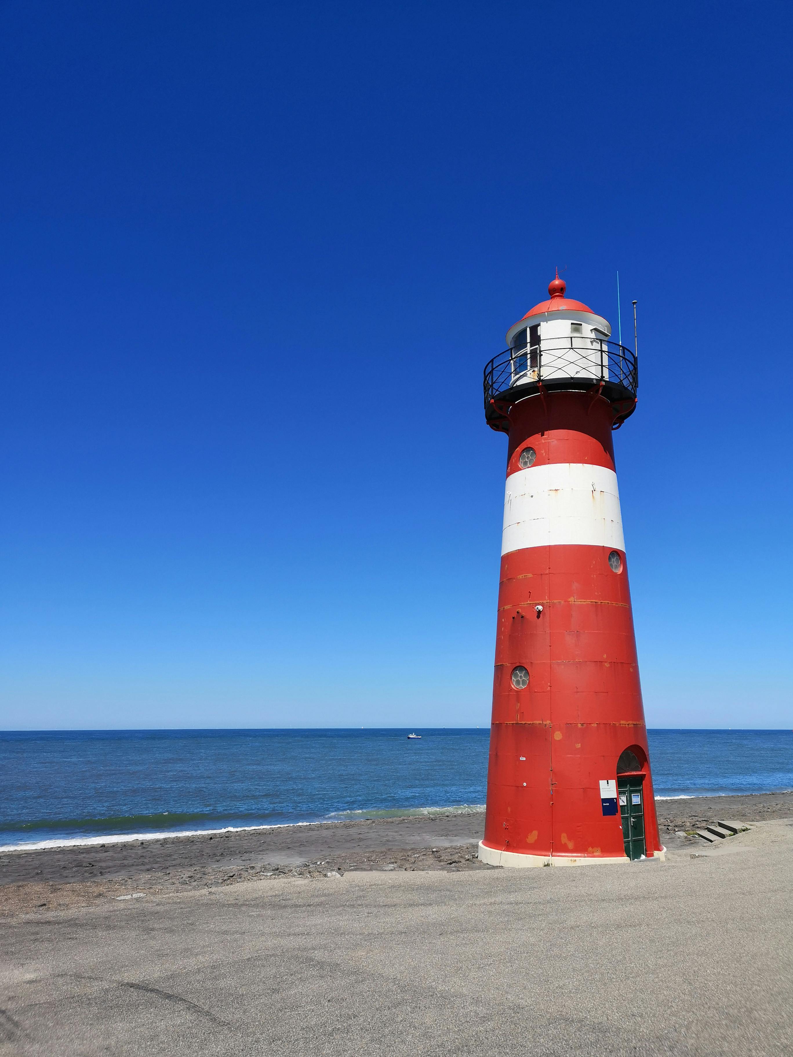 Red and White Lighthouse on Beach · Free Stock Photo