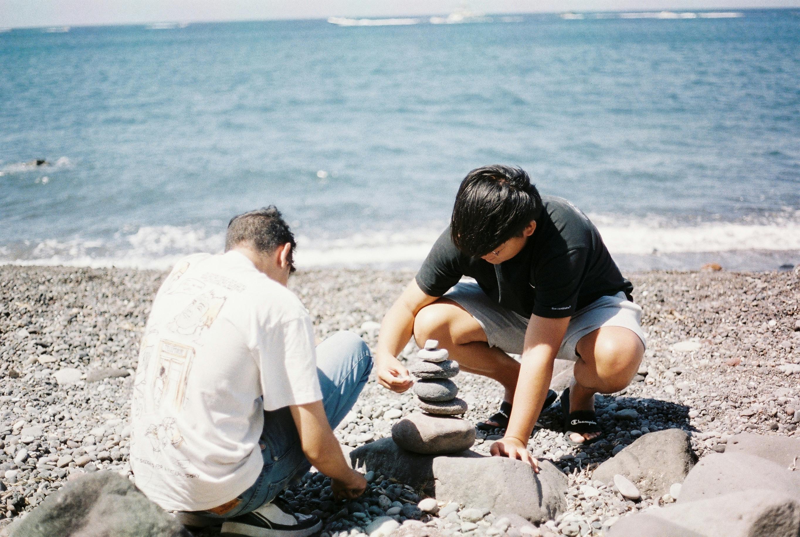 Young Men Balancing Rocks on the Beach · Free Stock Photo