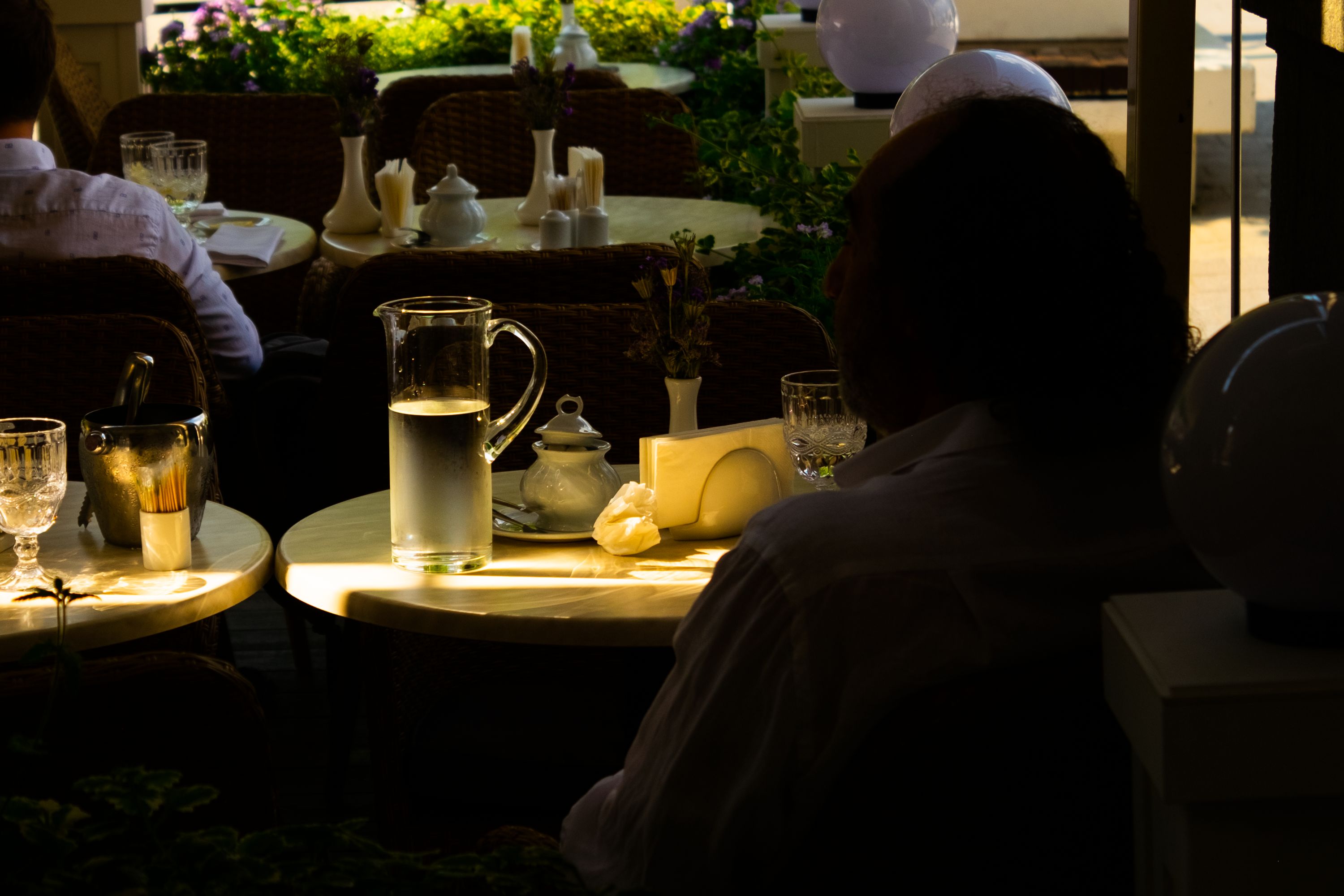 Person Sitting by Cafe Table with Water Jug · Free Stock Photo