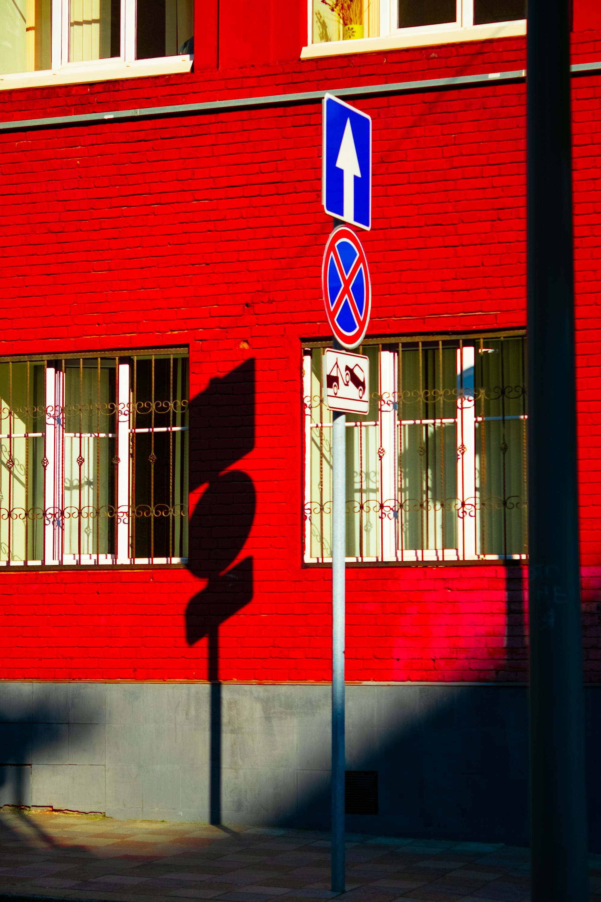 Road Signs outside a Building with Red Wall · Free Stock Photo