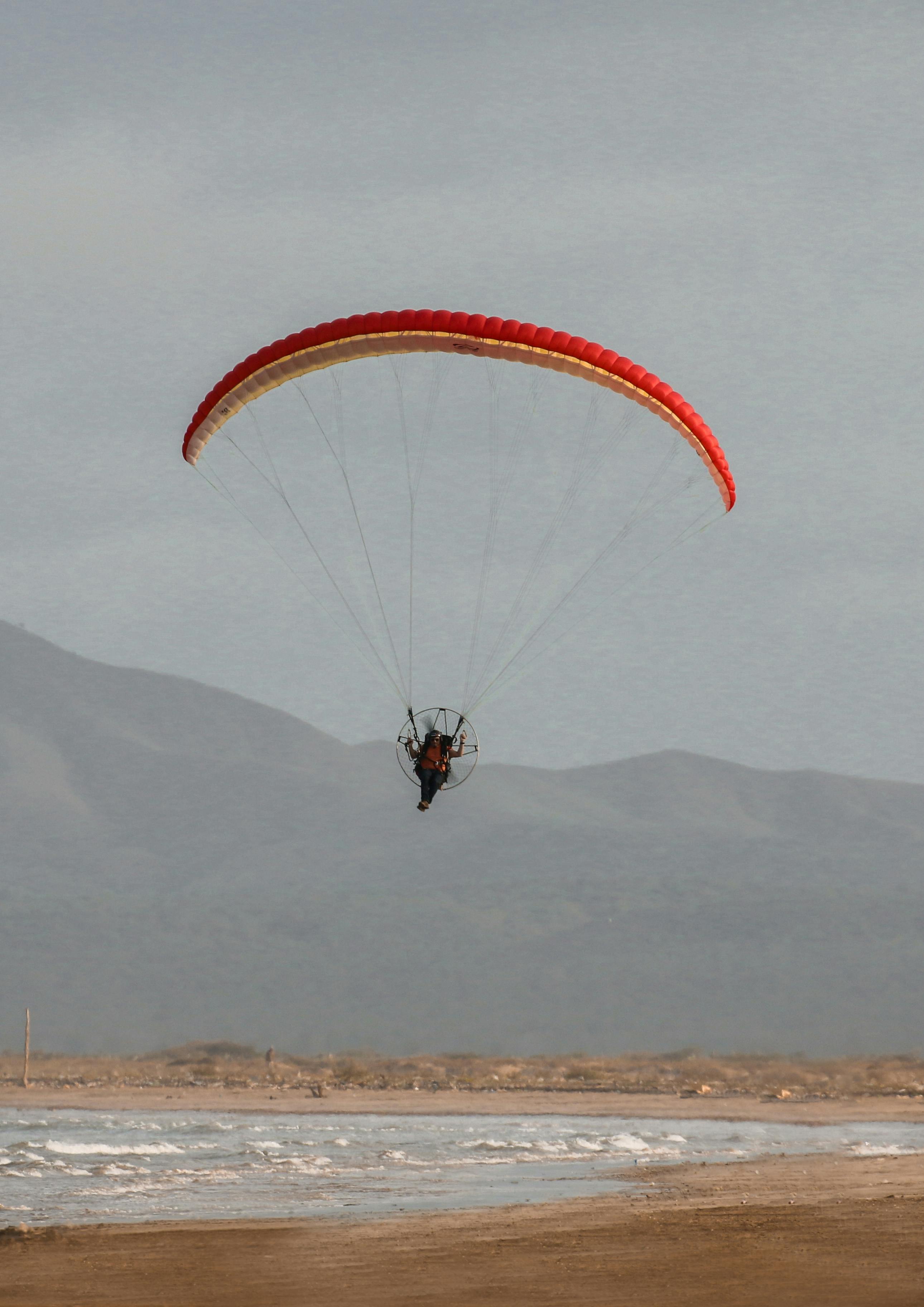 Man Flying on Parachute Near Green Trees · Free Stock Photo