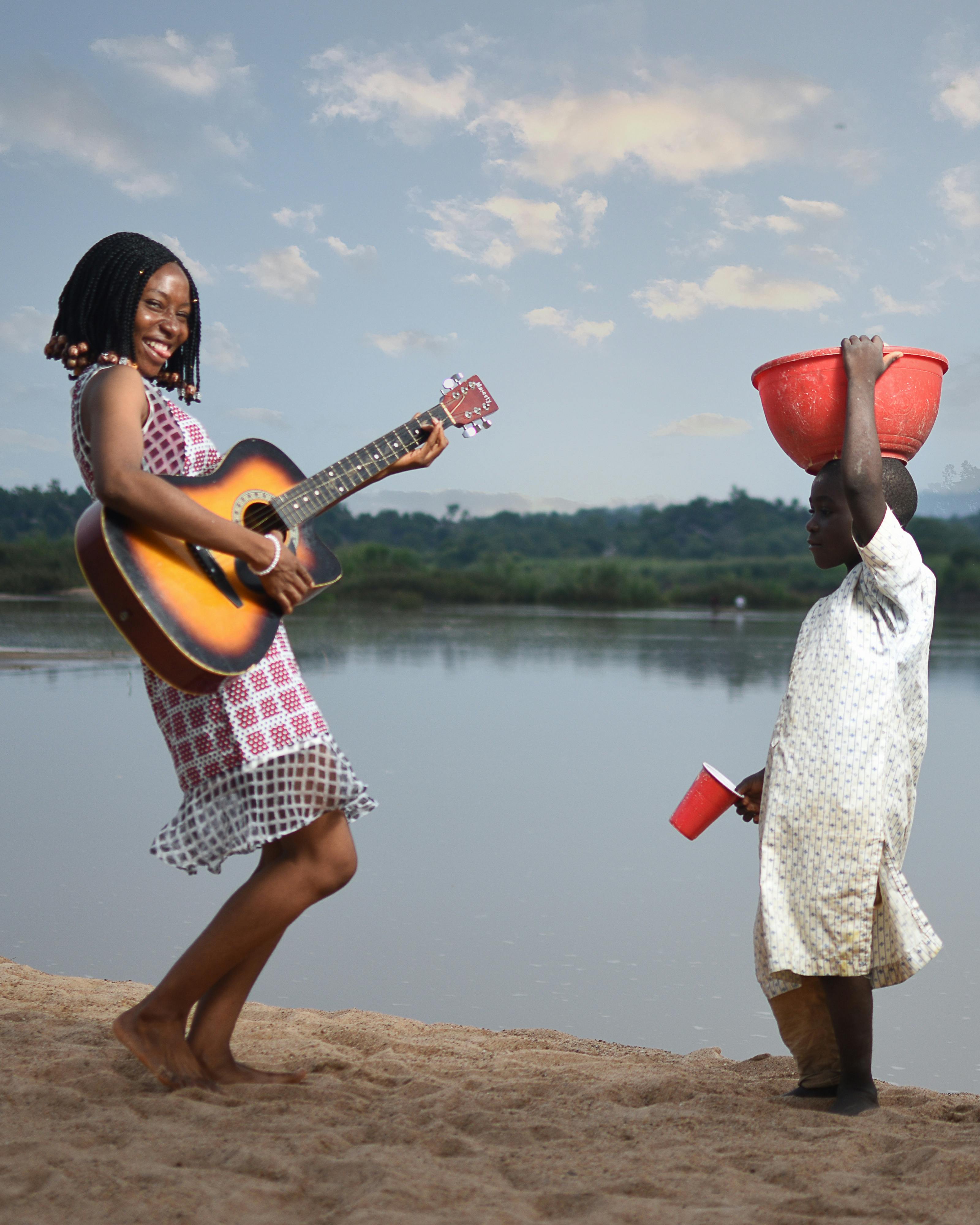 A Girl Playing the Guitar beside a Dancing Boy · Free Stock Photo