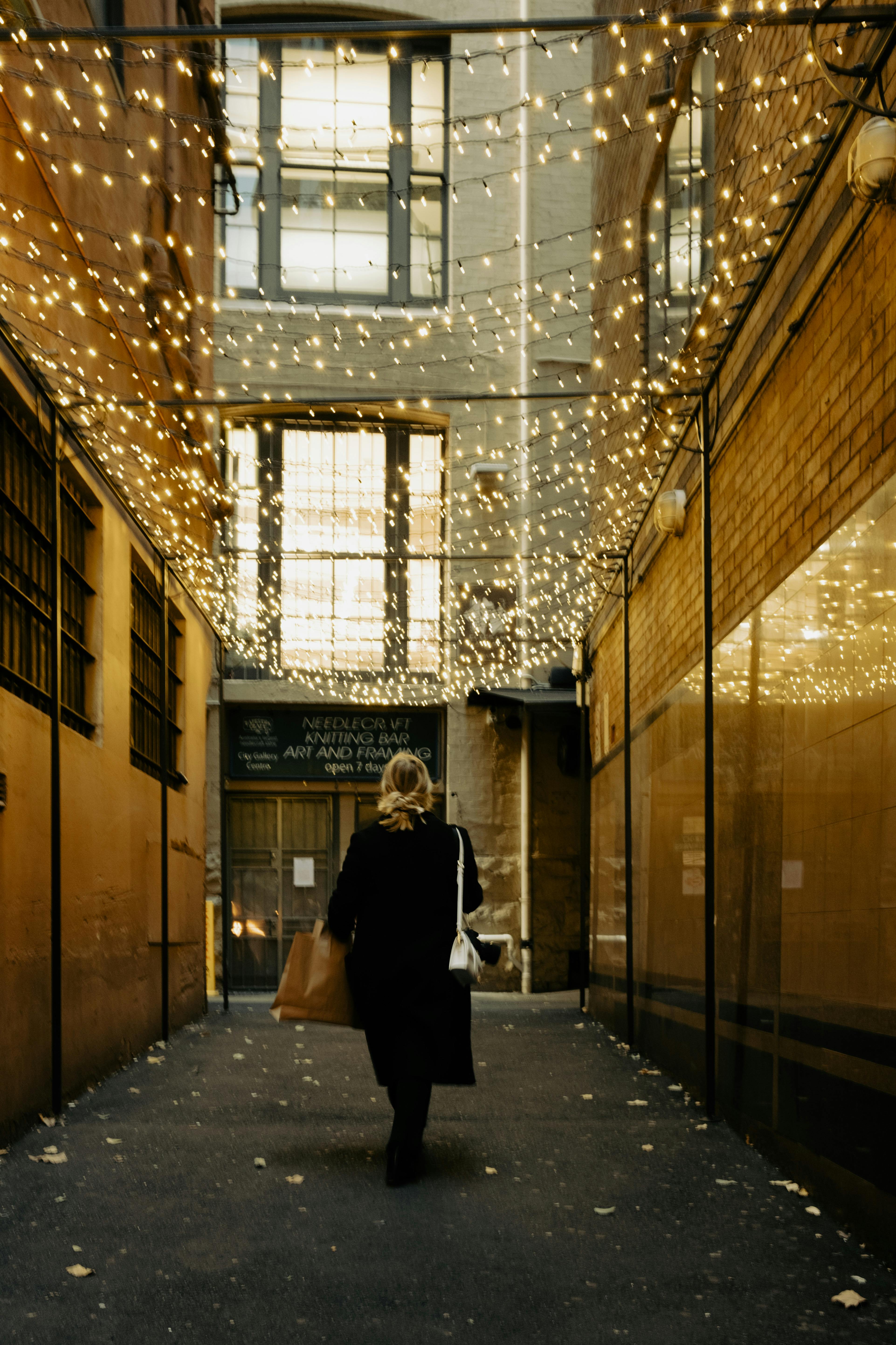 A Person Walking under String Lights in an Alley · Free Stock Photo