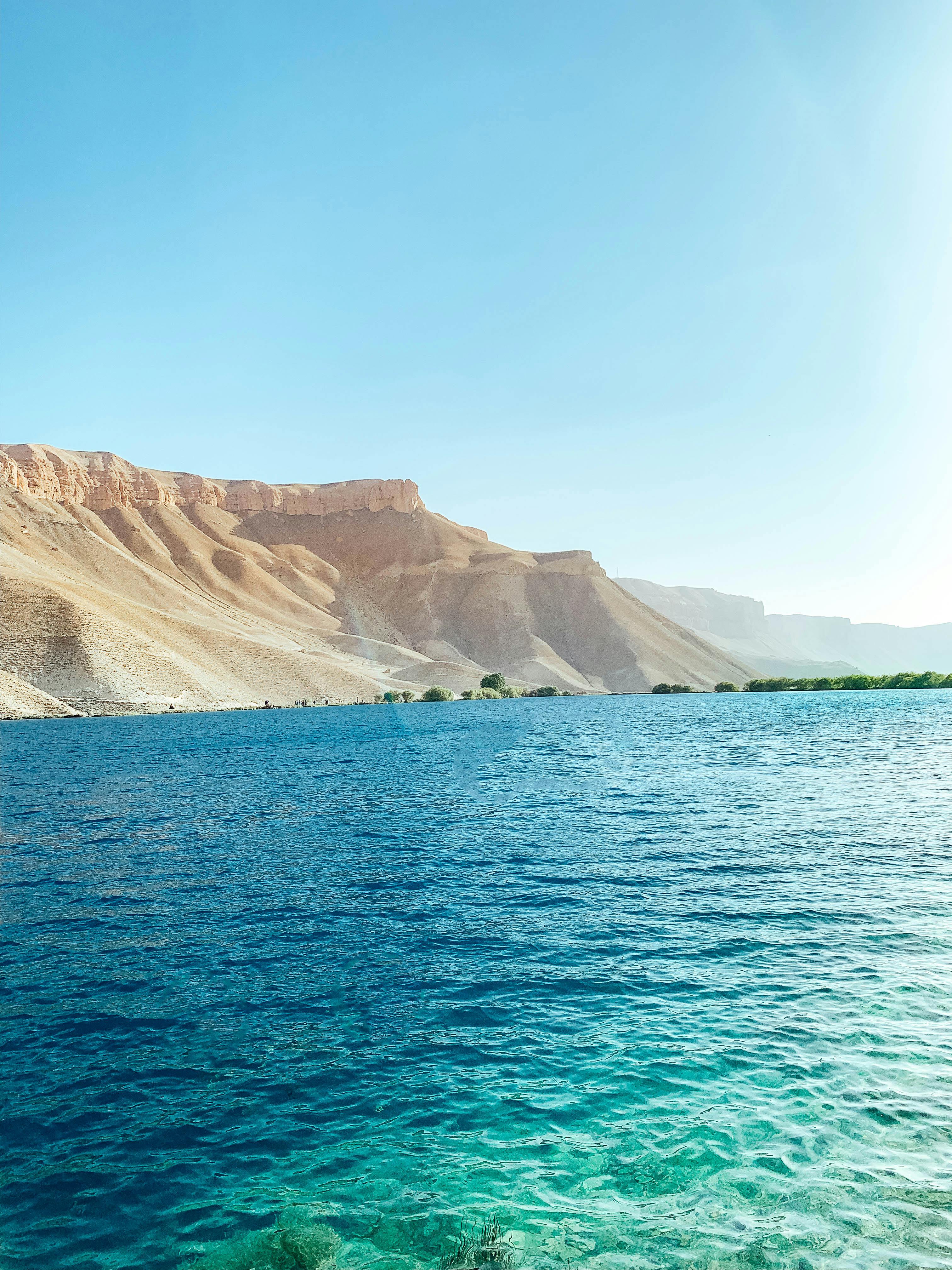 Blue Ocean near Brown Mountain under the Blue Sky · Free Stock Photo