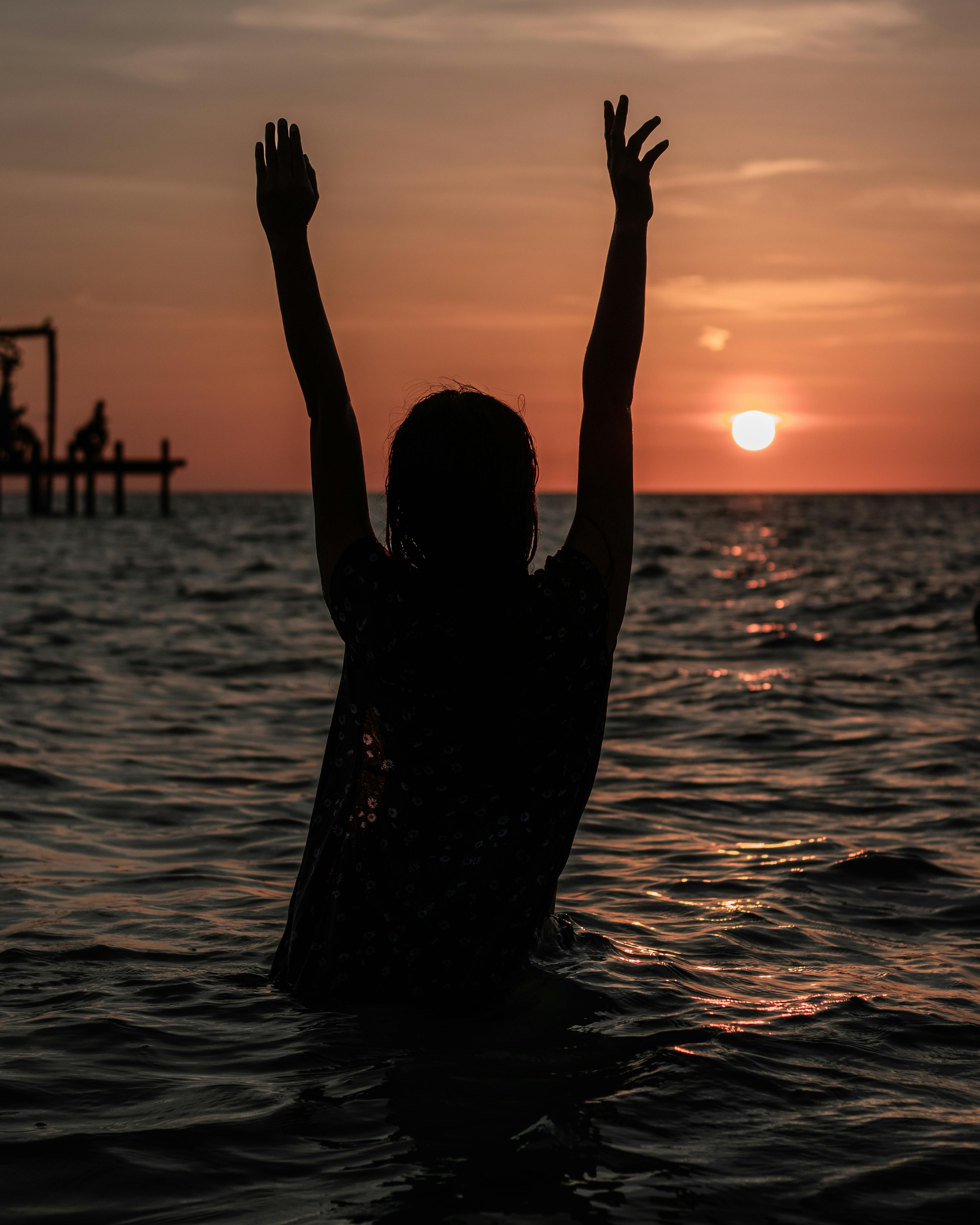Silhouette of a Person Raising Her Hands · Free Stock Photo