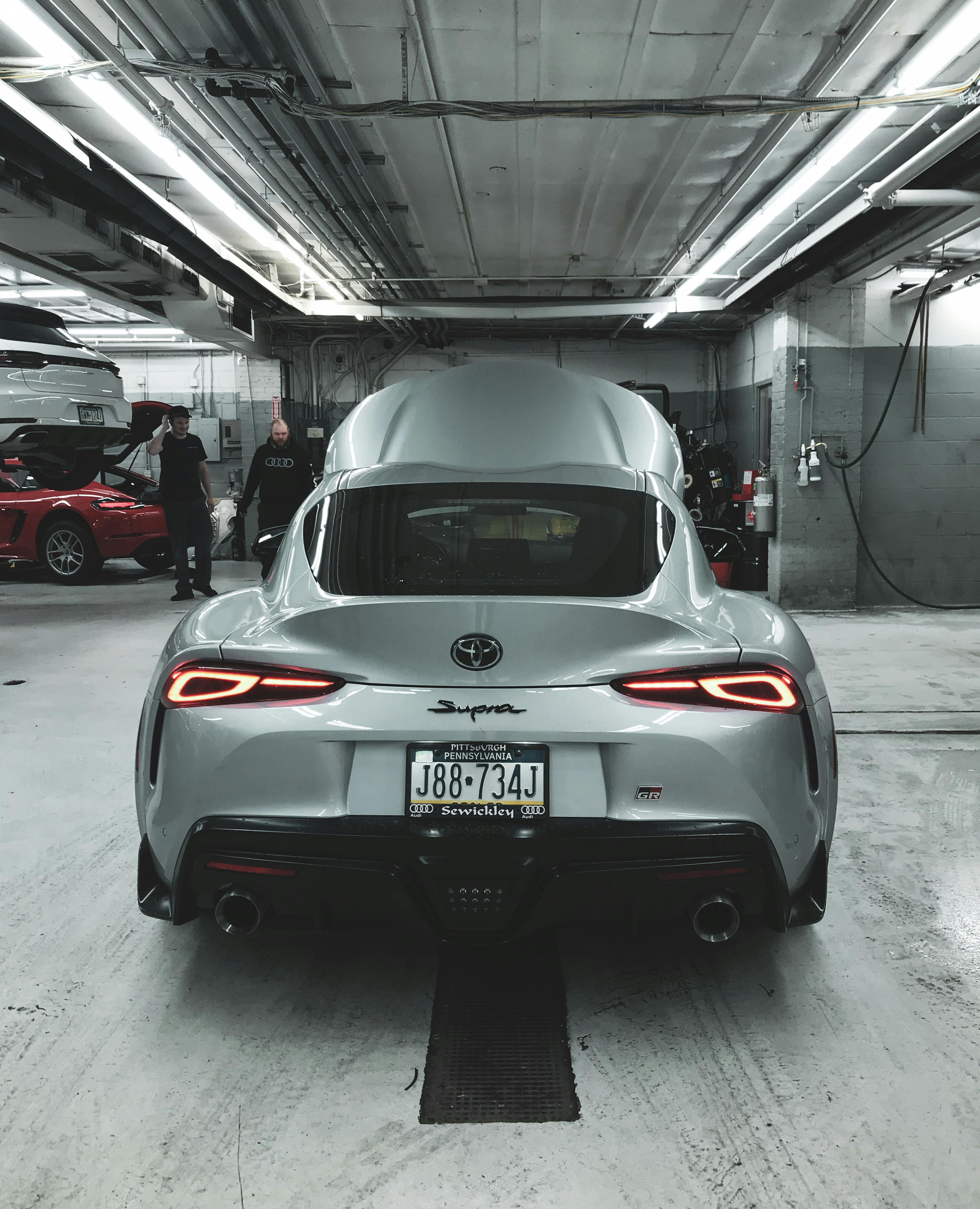 Modern Car with Spoiler near Garage Building · Free Stock Photo