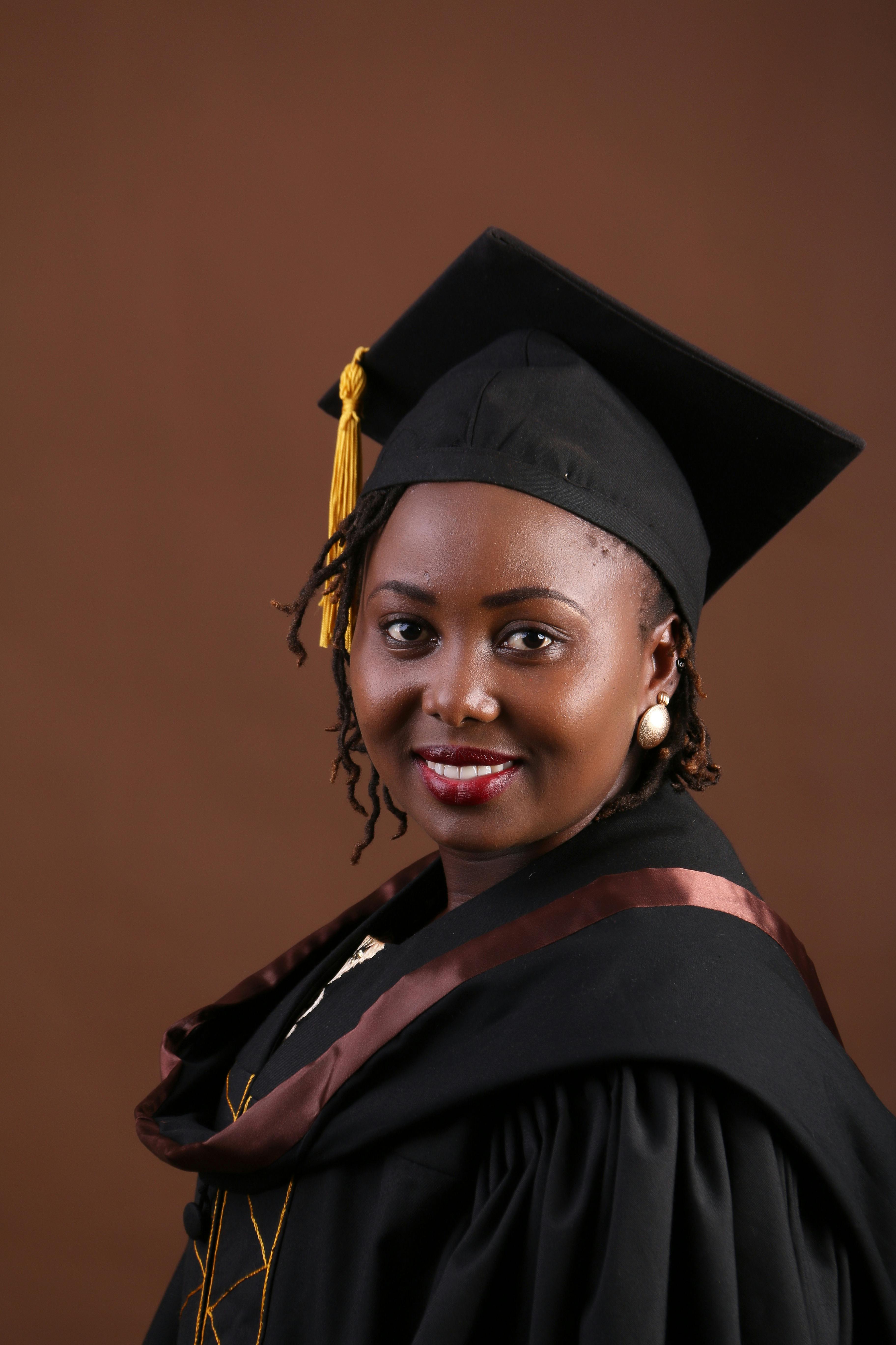 A Man Wearing Black Toga and Graduation Cap Holding a Small Board while ...