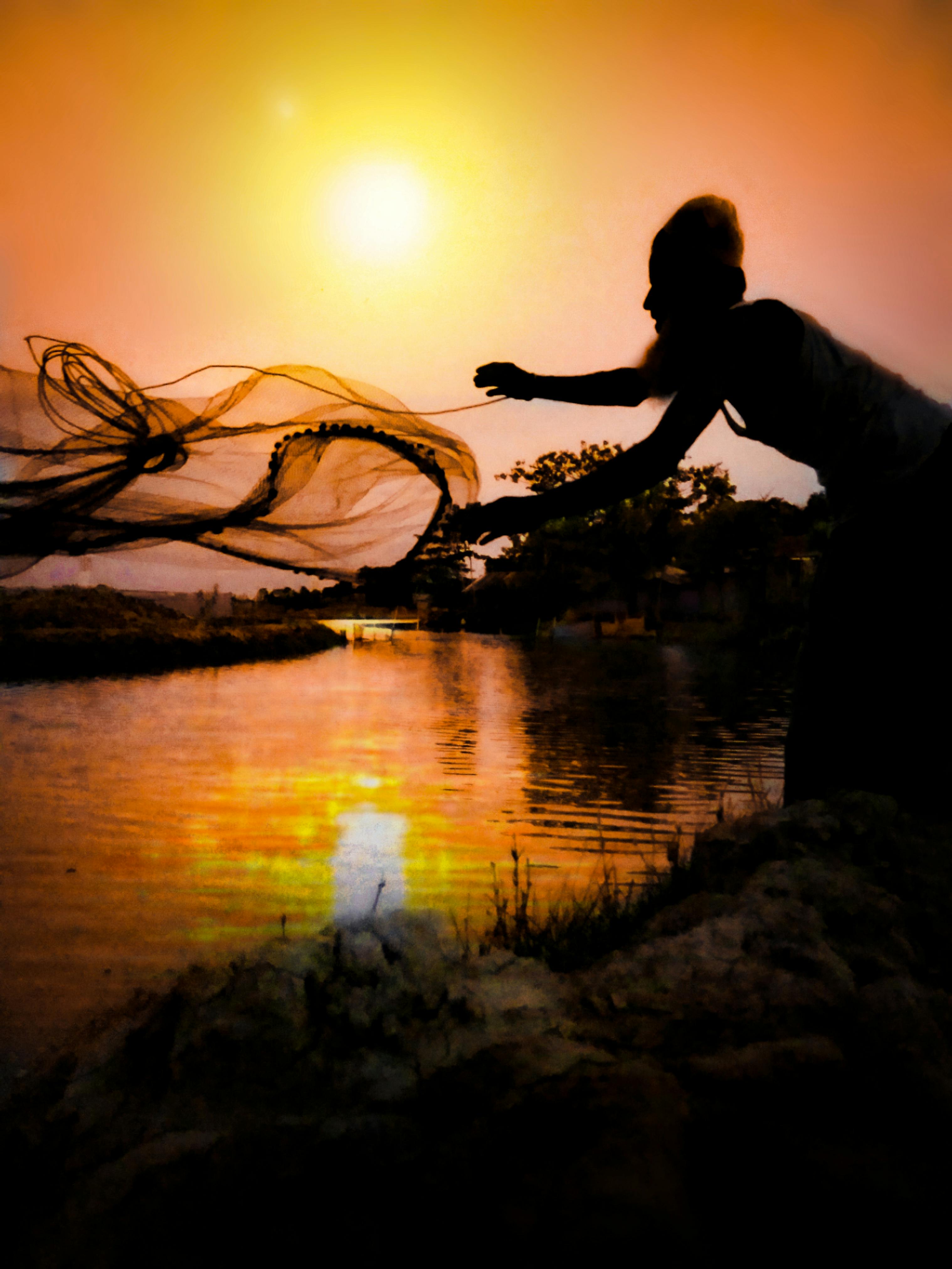 Silhouette of Man Throwing Fishnet · Free Stock Photo