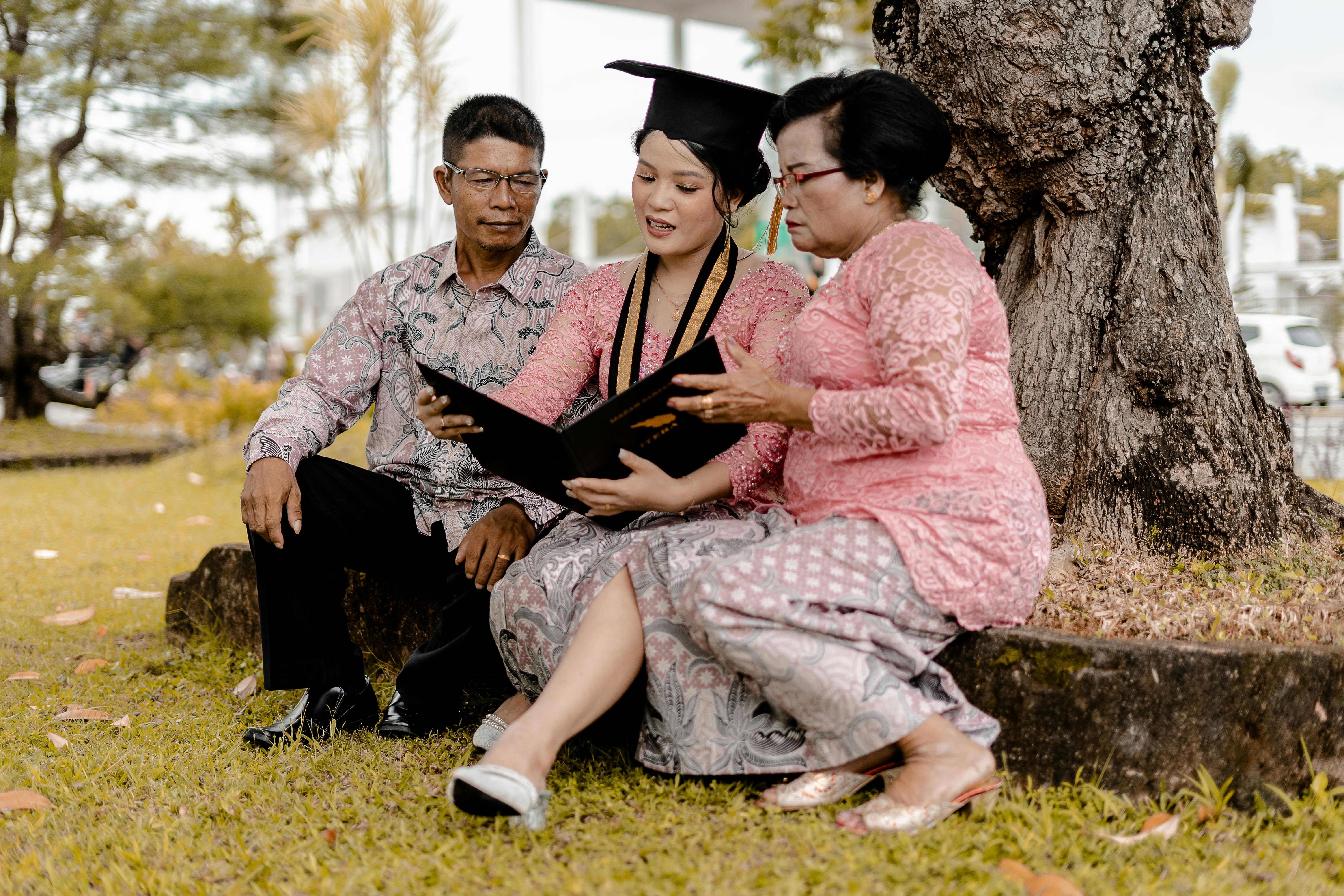 Parents and Their Daughter Looking at a Diploma · Free Stock Photo