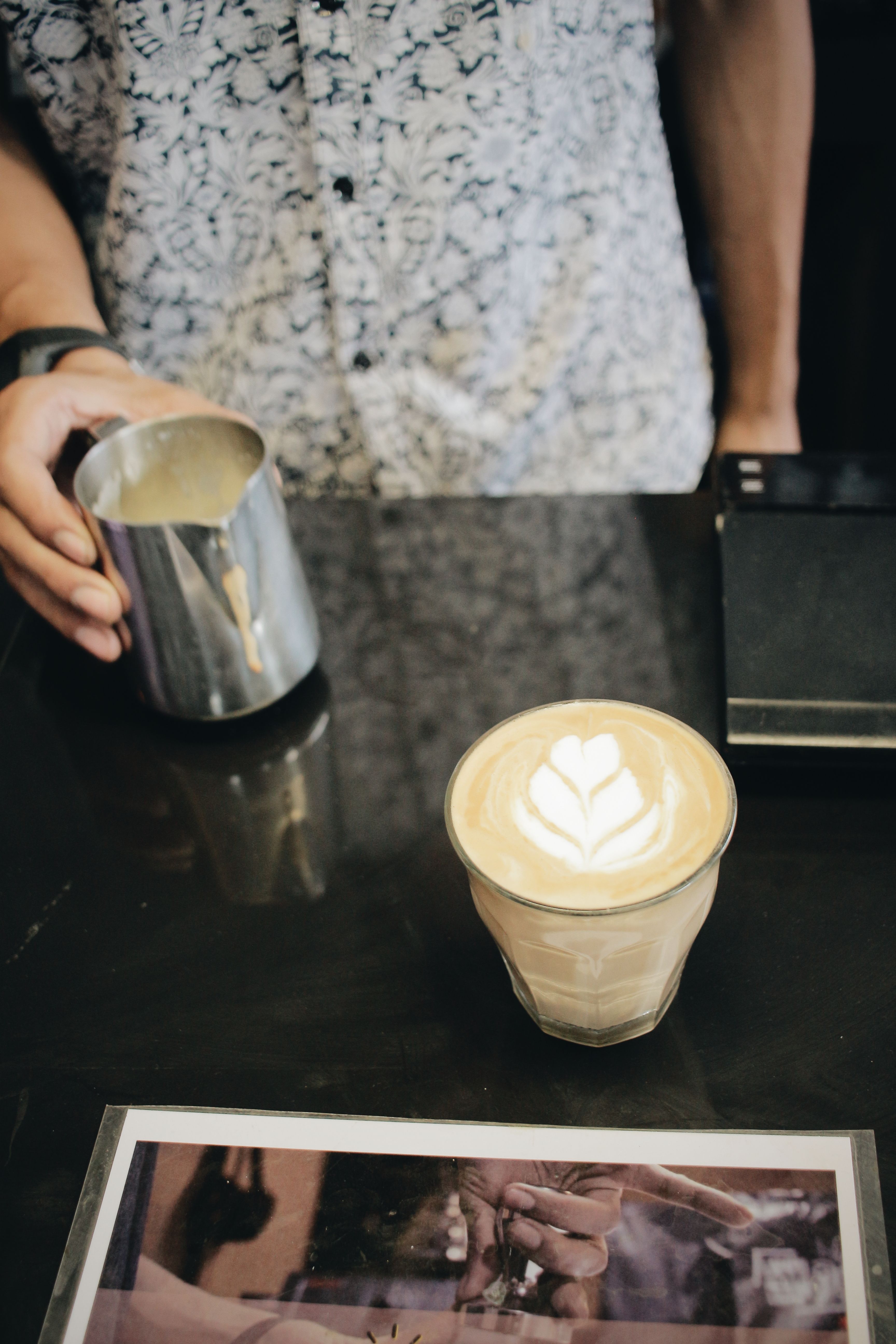 Person Holding Stainless Pitcher Beside a Cup of Coffee · Free Stock Photo