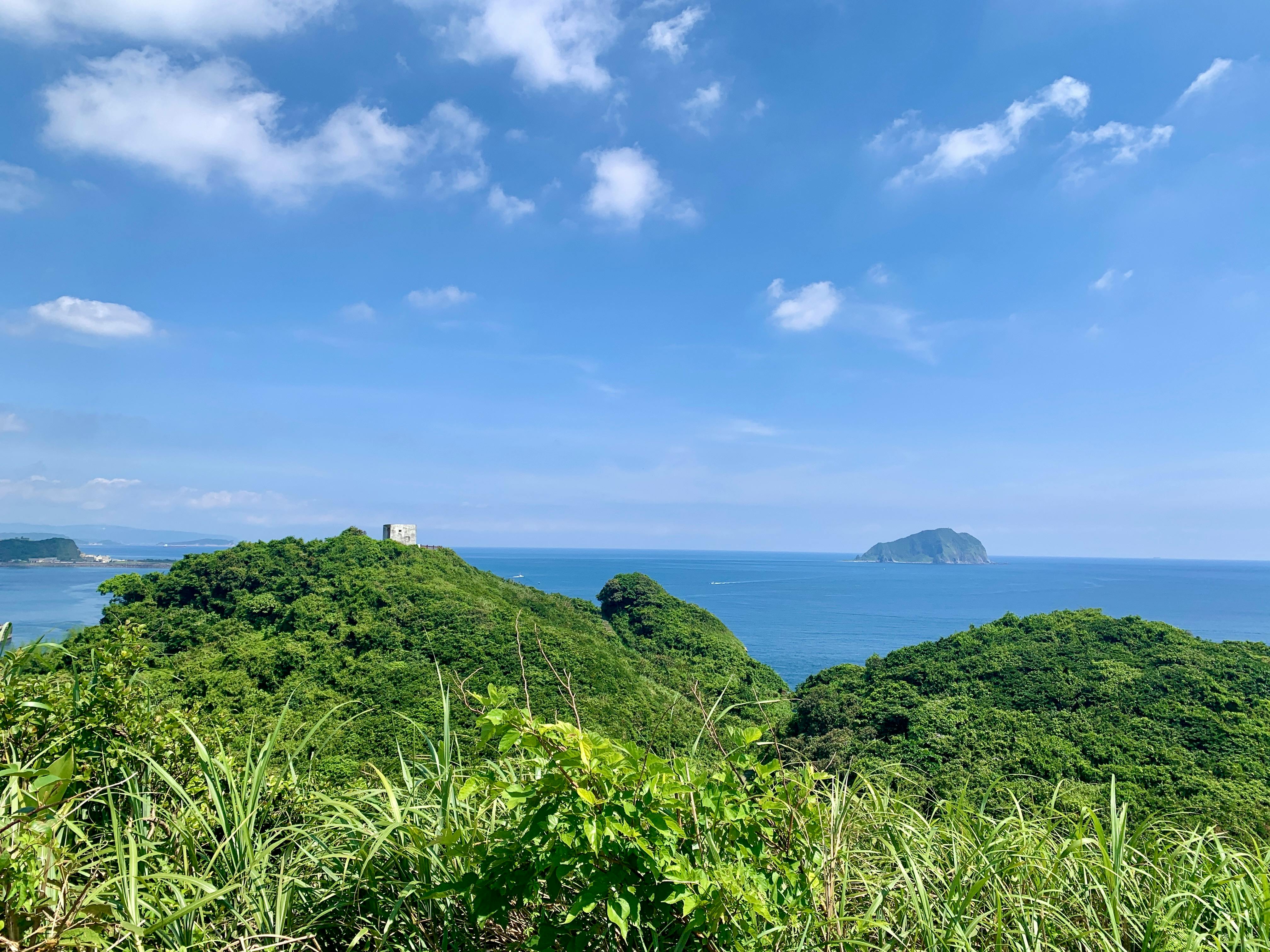 A Green Grass Near the Body of Water Under the Blue Sky · Free Stock Photo