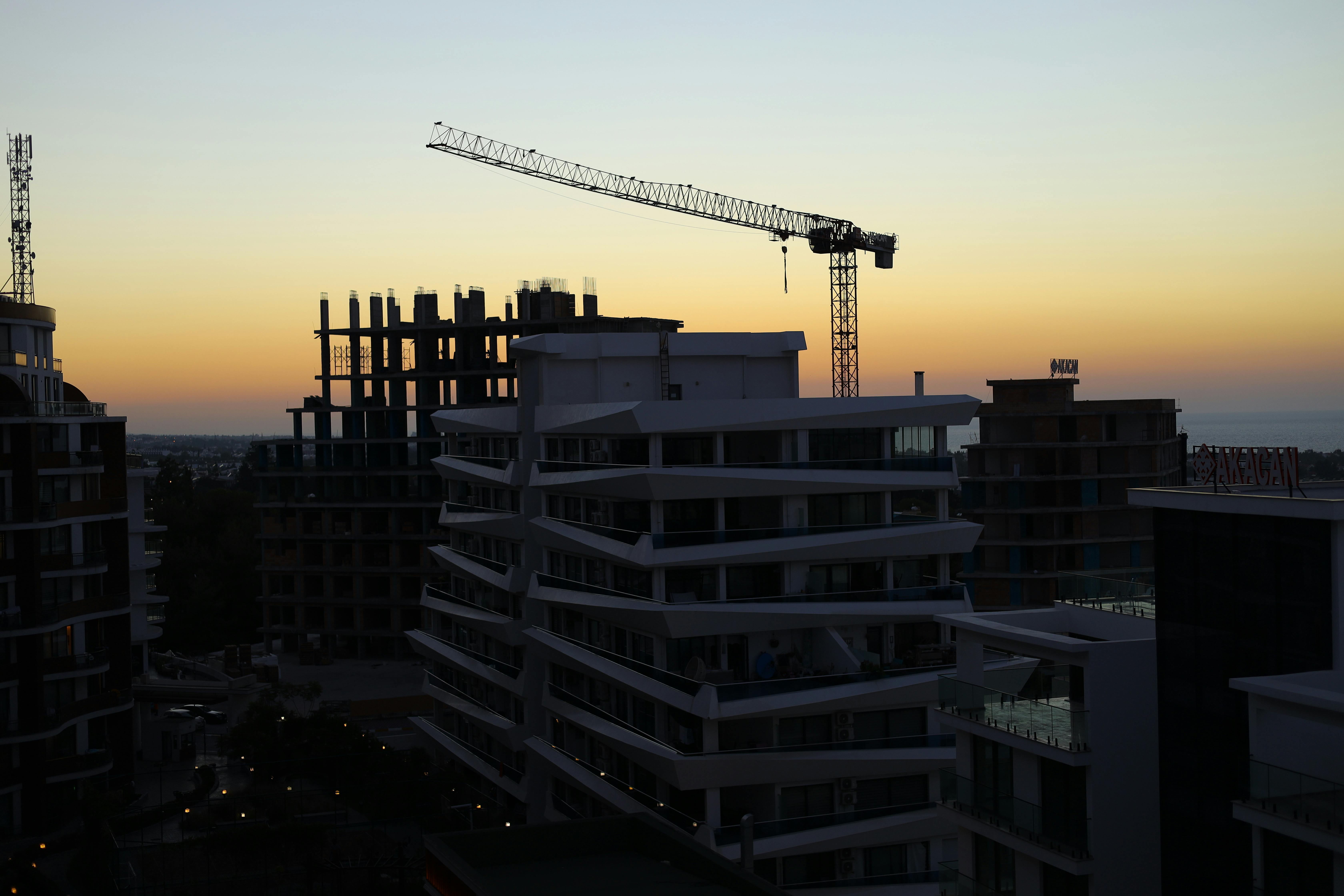 Construction Crane over Buildings at Sunset · Free Stock Photo
