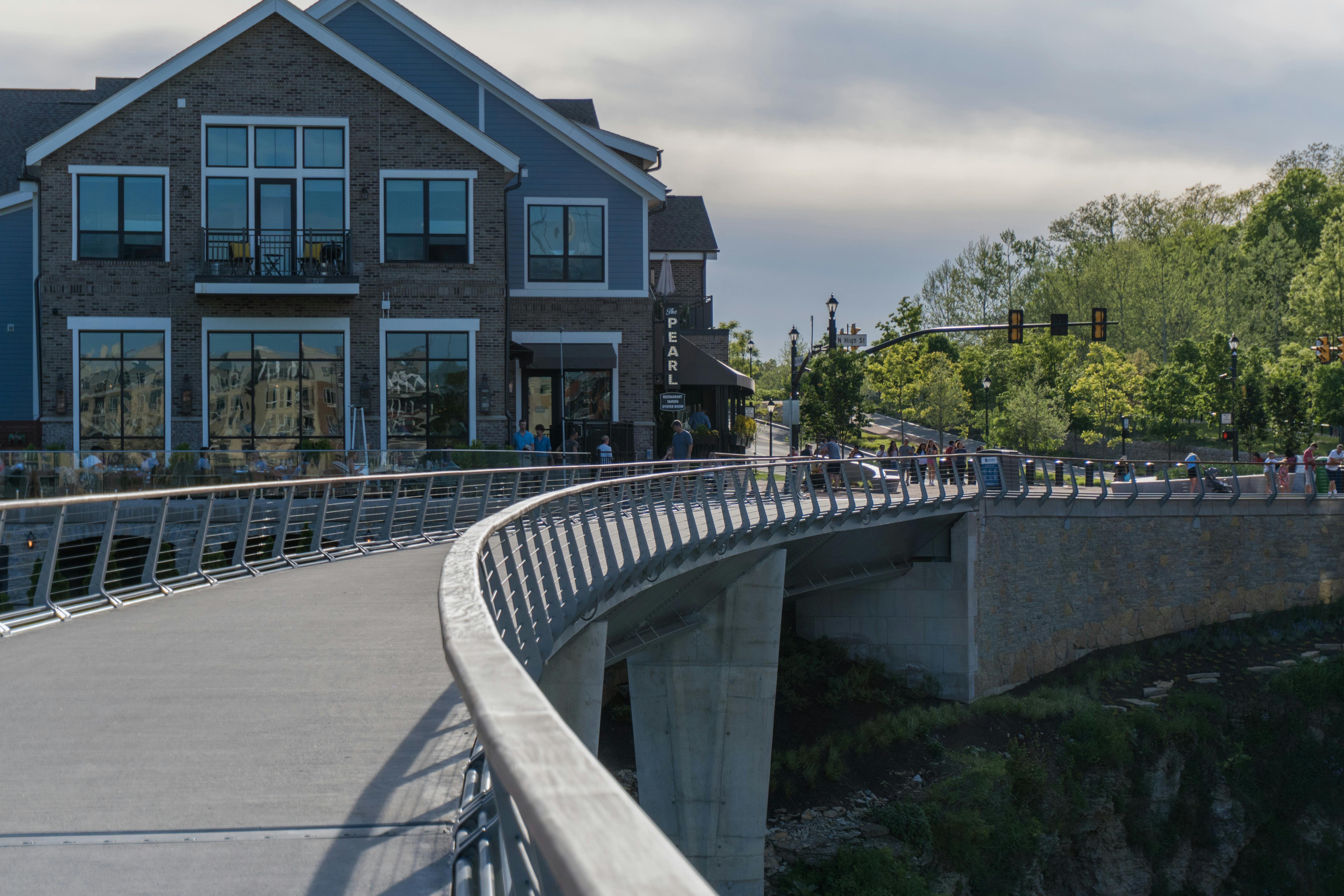 A Concrete Pedestrian Bridge Near a Brown Building with Glass Windows ...