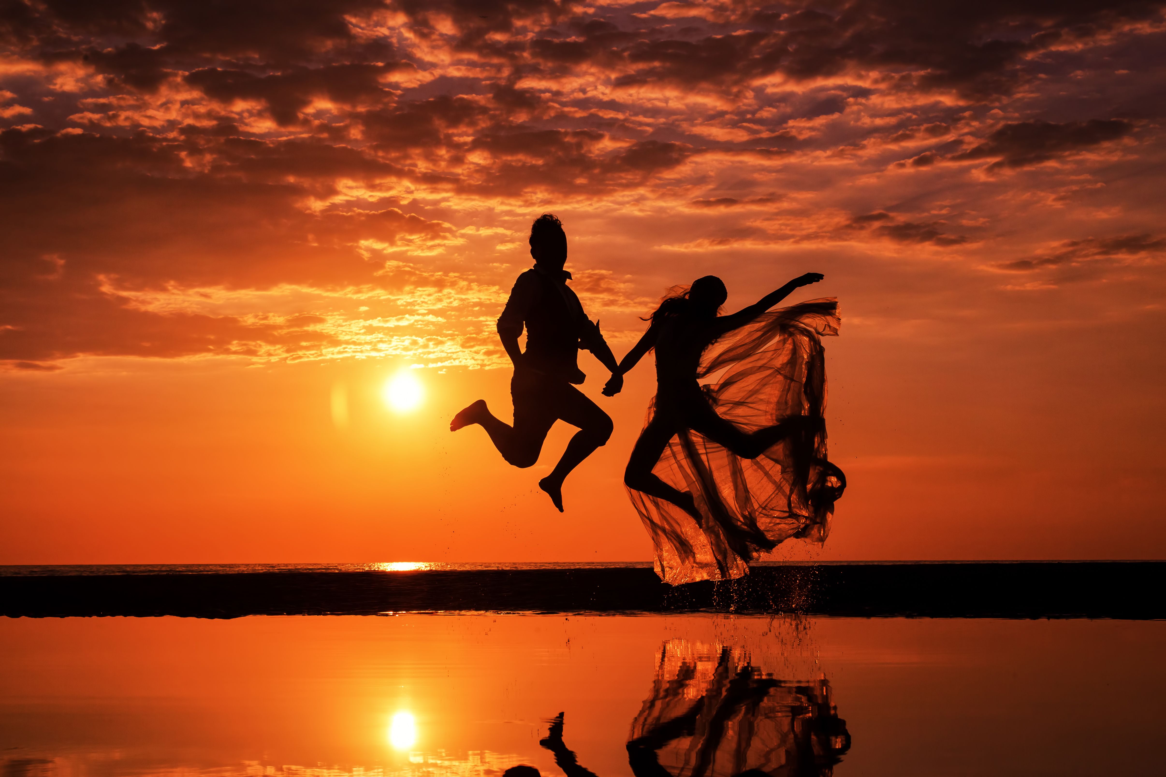 A Jump Shot of a Couple During Sunset · Free Stock Photo