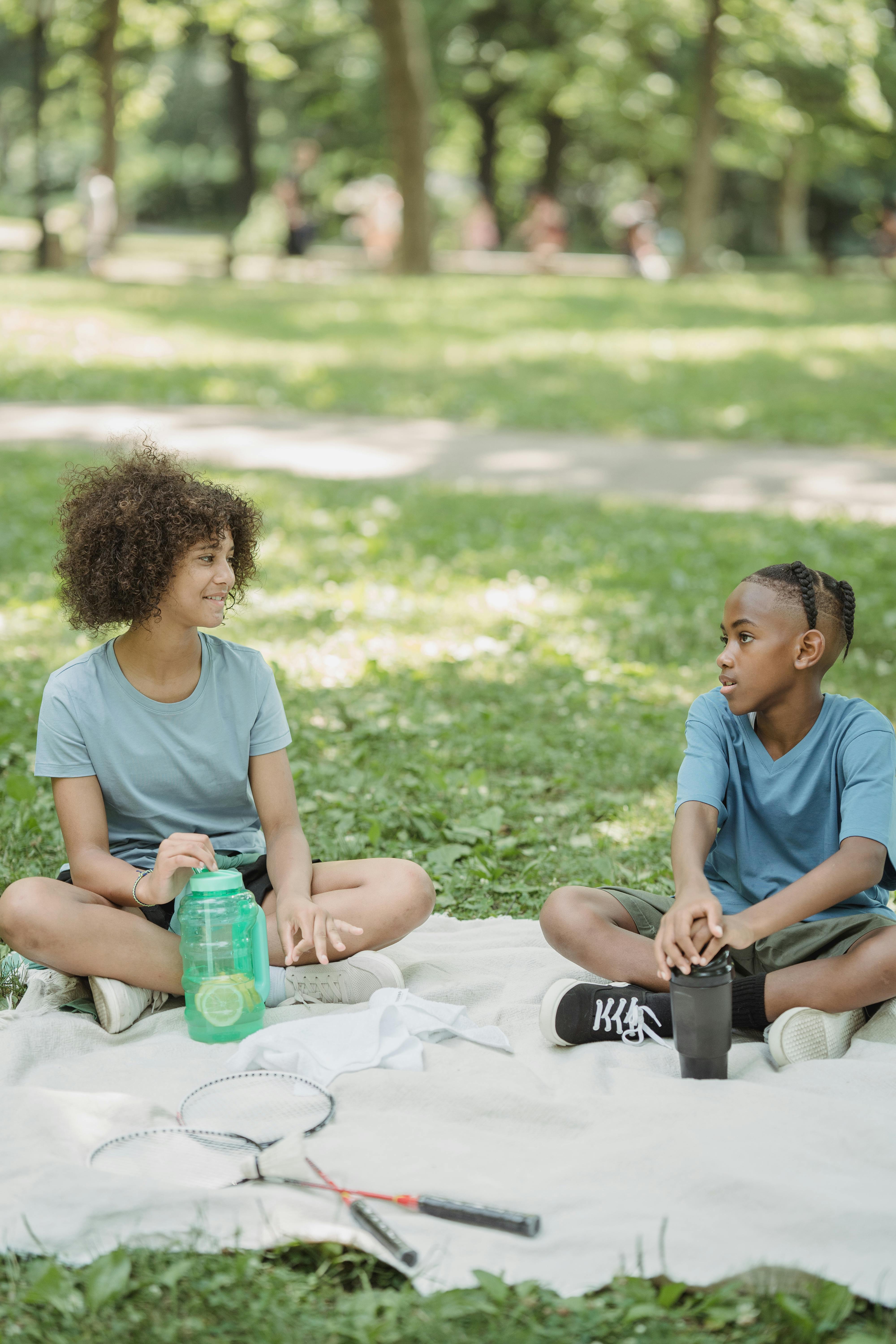 Teenagers Sitting on Blanket on Park Lawn and Talking · Free Stock Photo