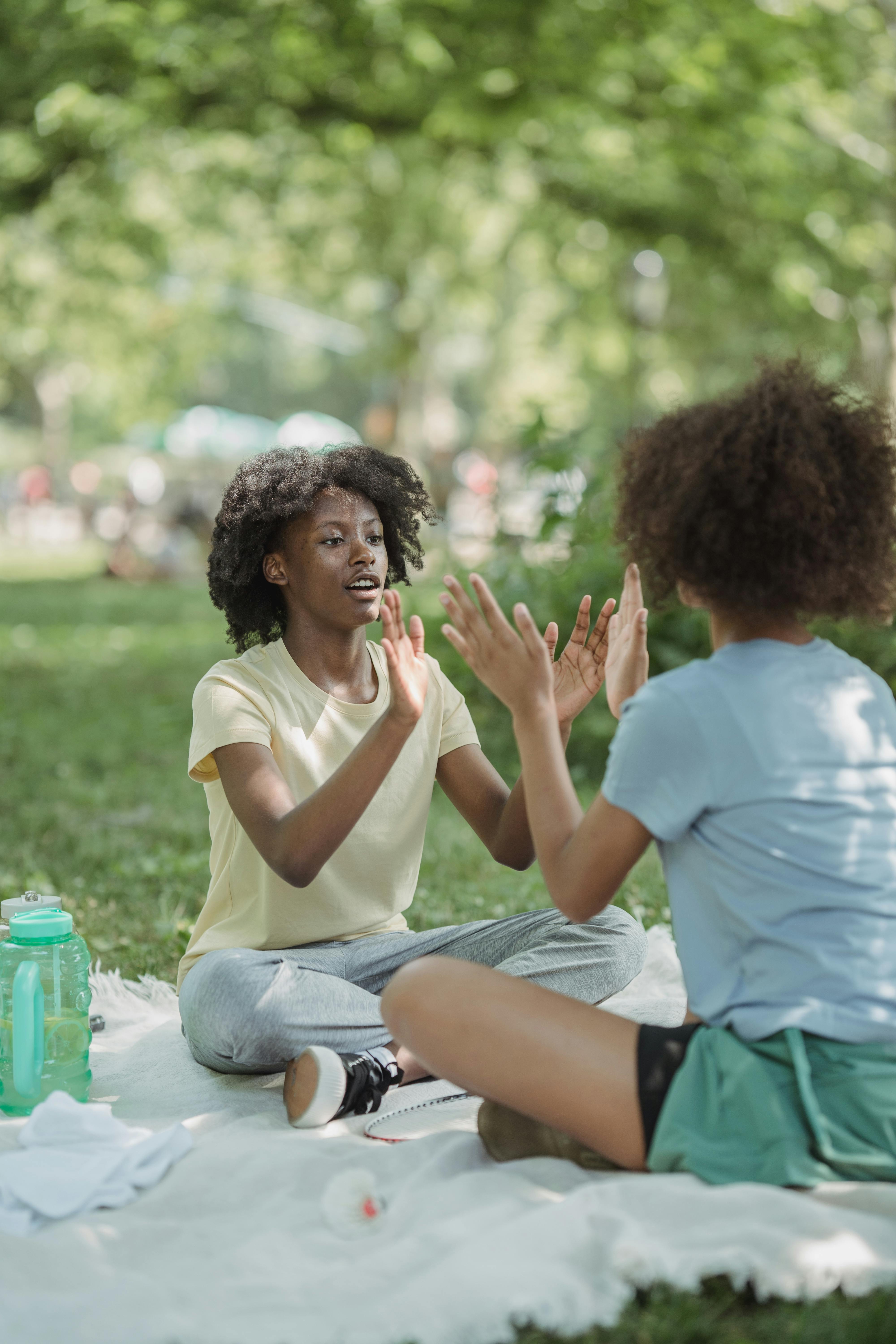 Two Teenage Girls Having Playing Patty Cake in the Park · Free Stock Photo