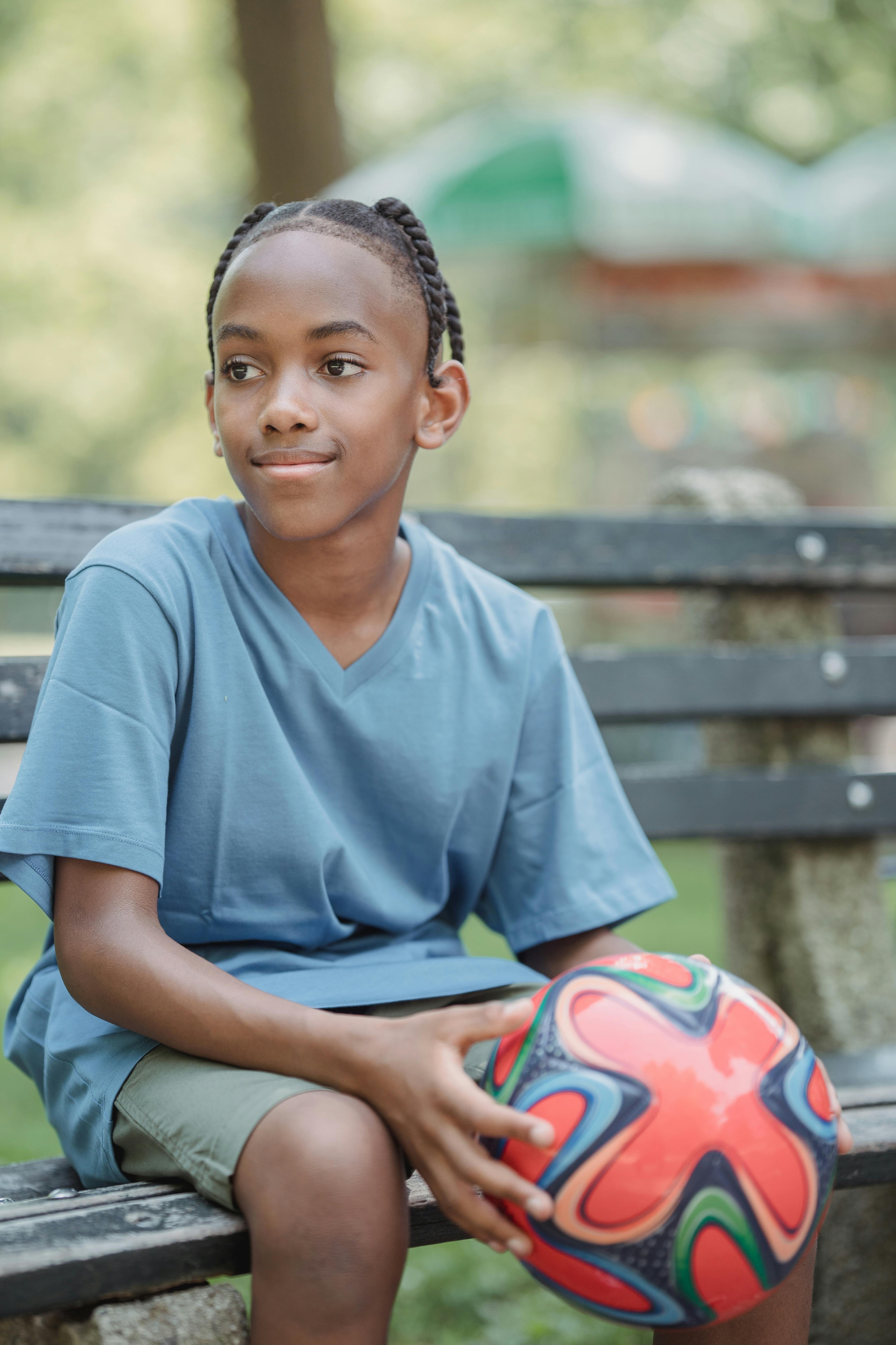 Boy Sitting on the Bench and Holding a Ball · Free Stock Photo