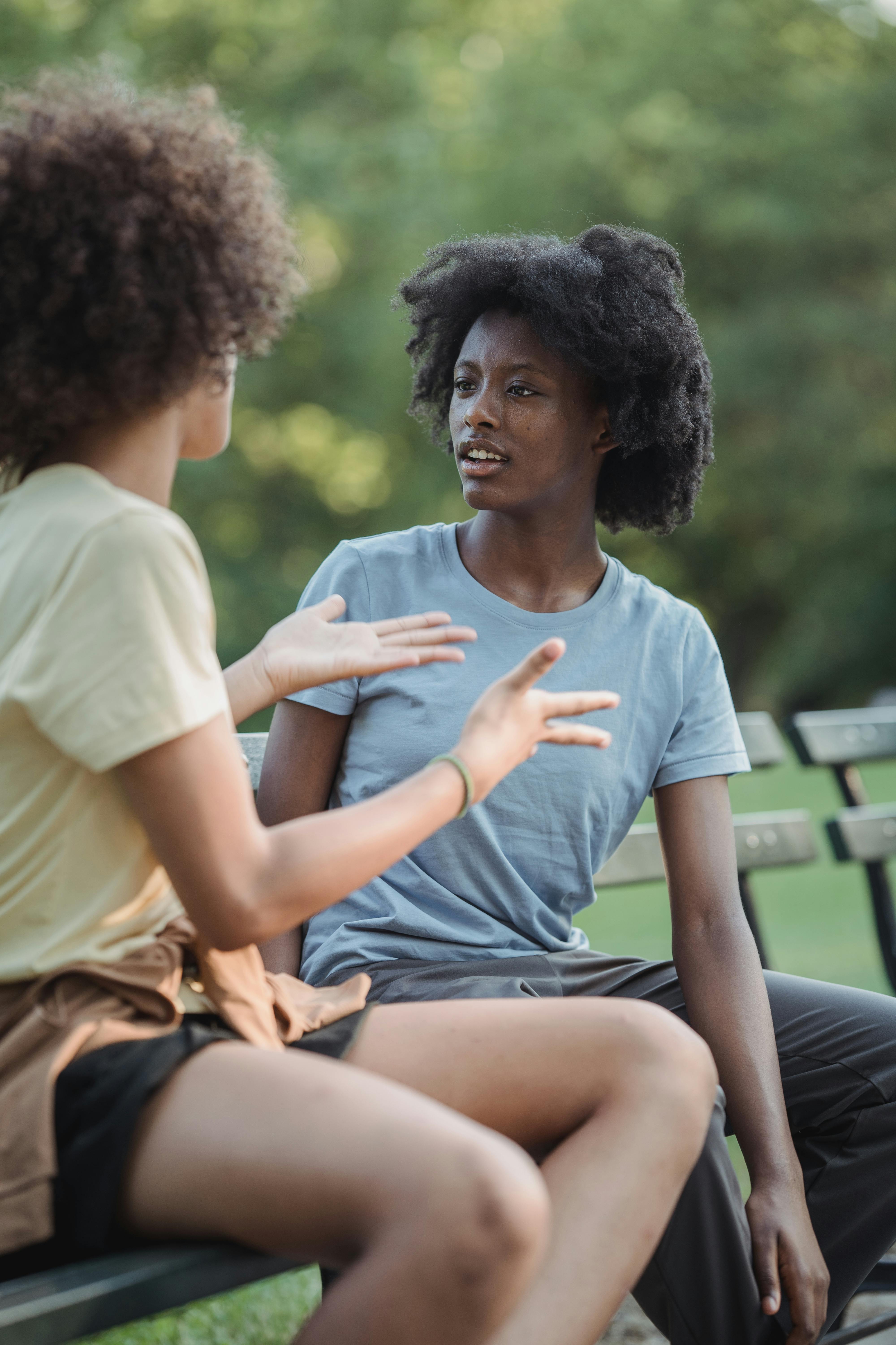 Young Women Sitting on a Park Bench and Talking · Free Stock Photo