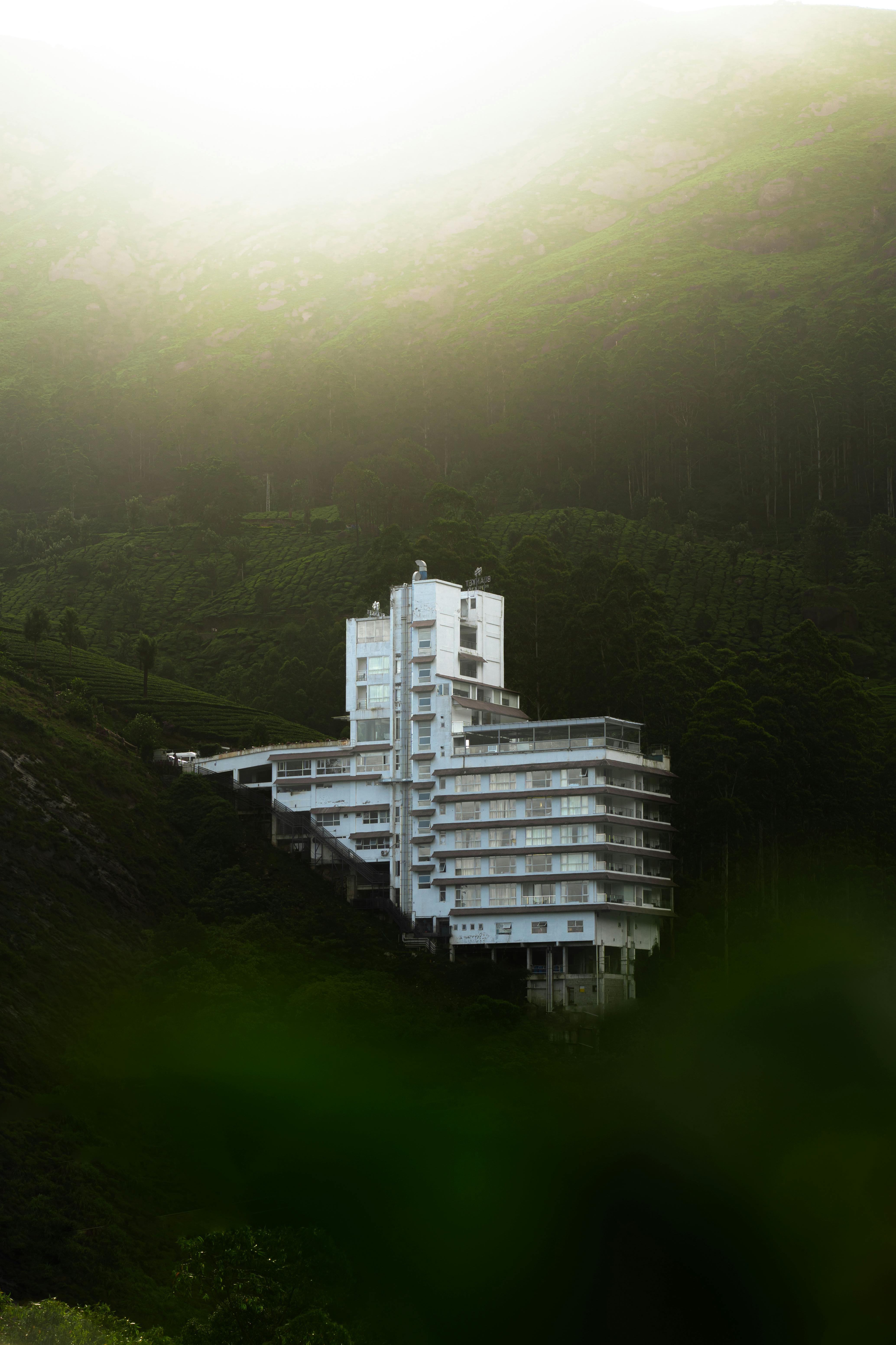 High Rise White Concrete Building on Green Mountain · Free Stock Photo