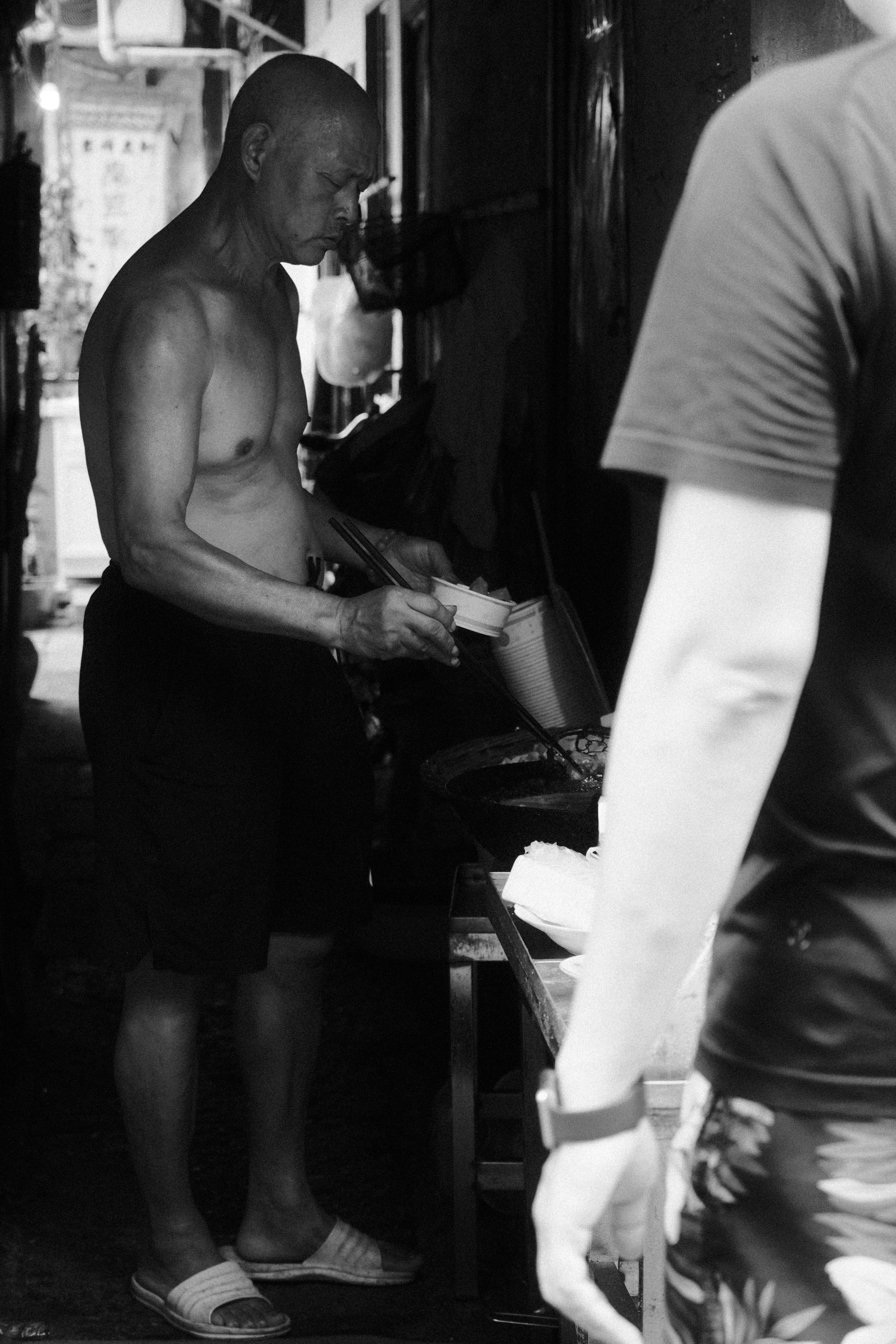 A Grayscale of a Shirtless Man Cooking · Free Stock Photo