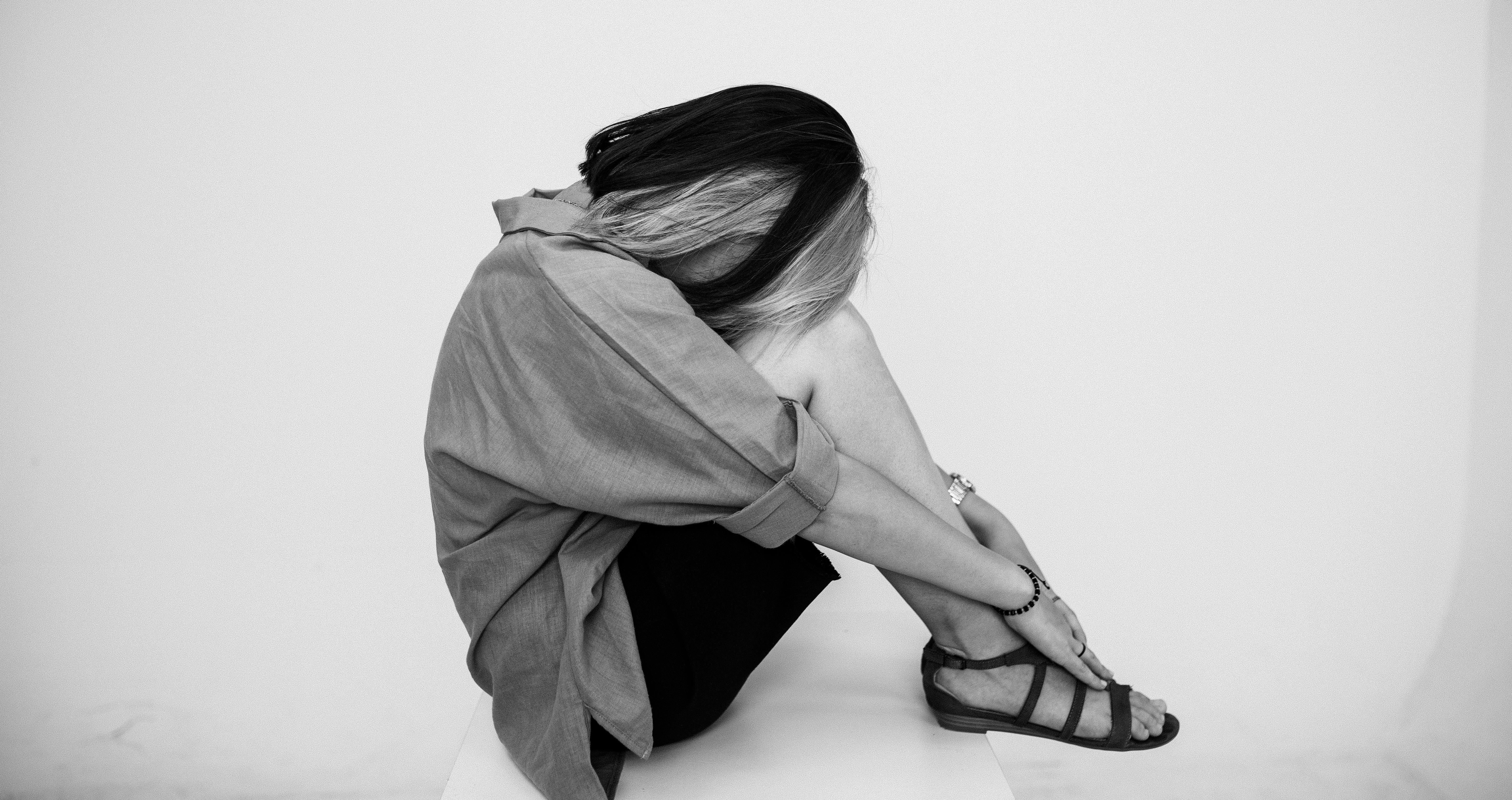 A Grayscale of a Woman Curled Up · Free Stock Photo