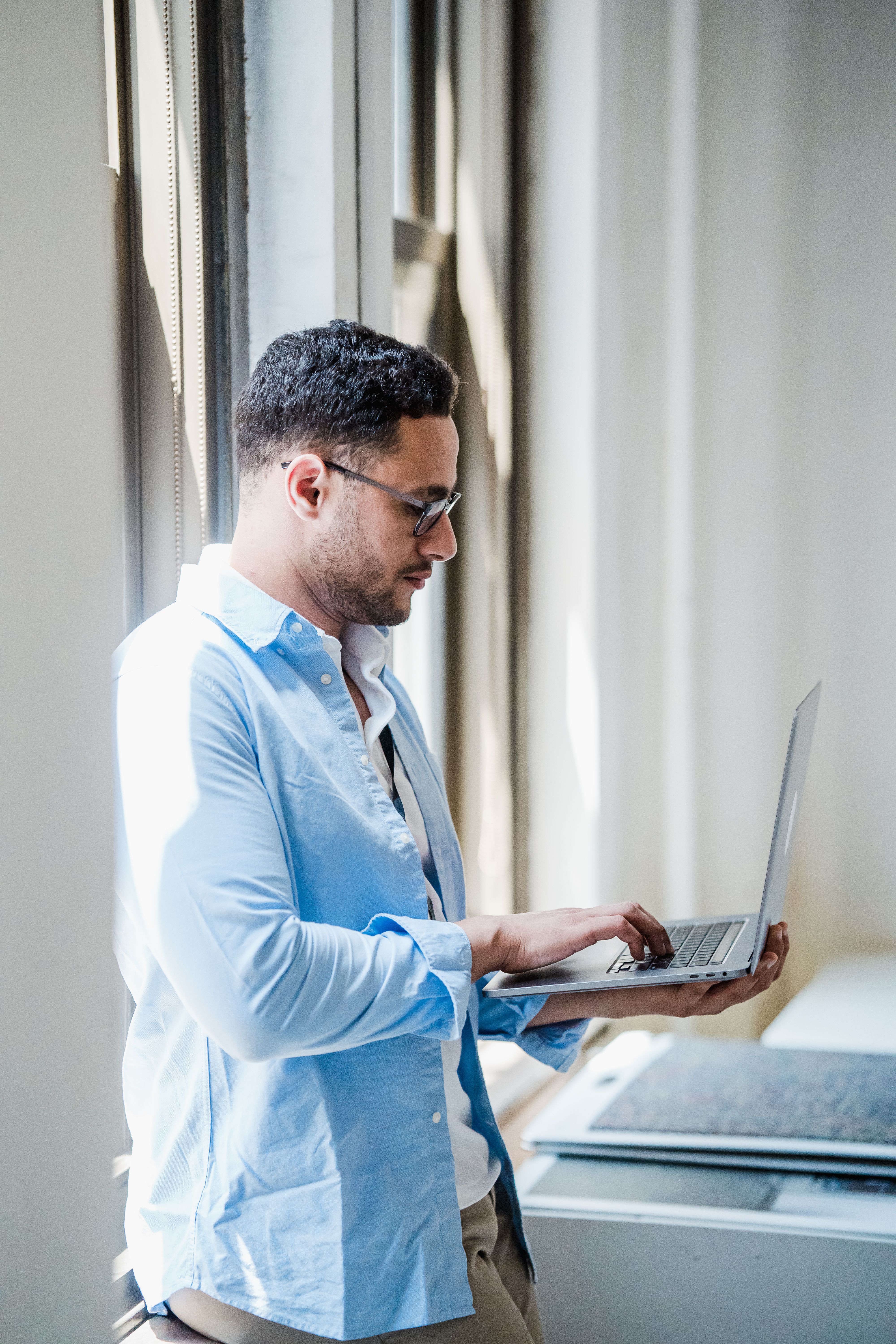 Man Standing Working on Laptop in Office · Free Stock Photo
