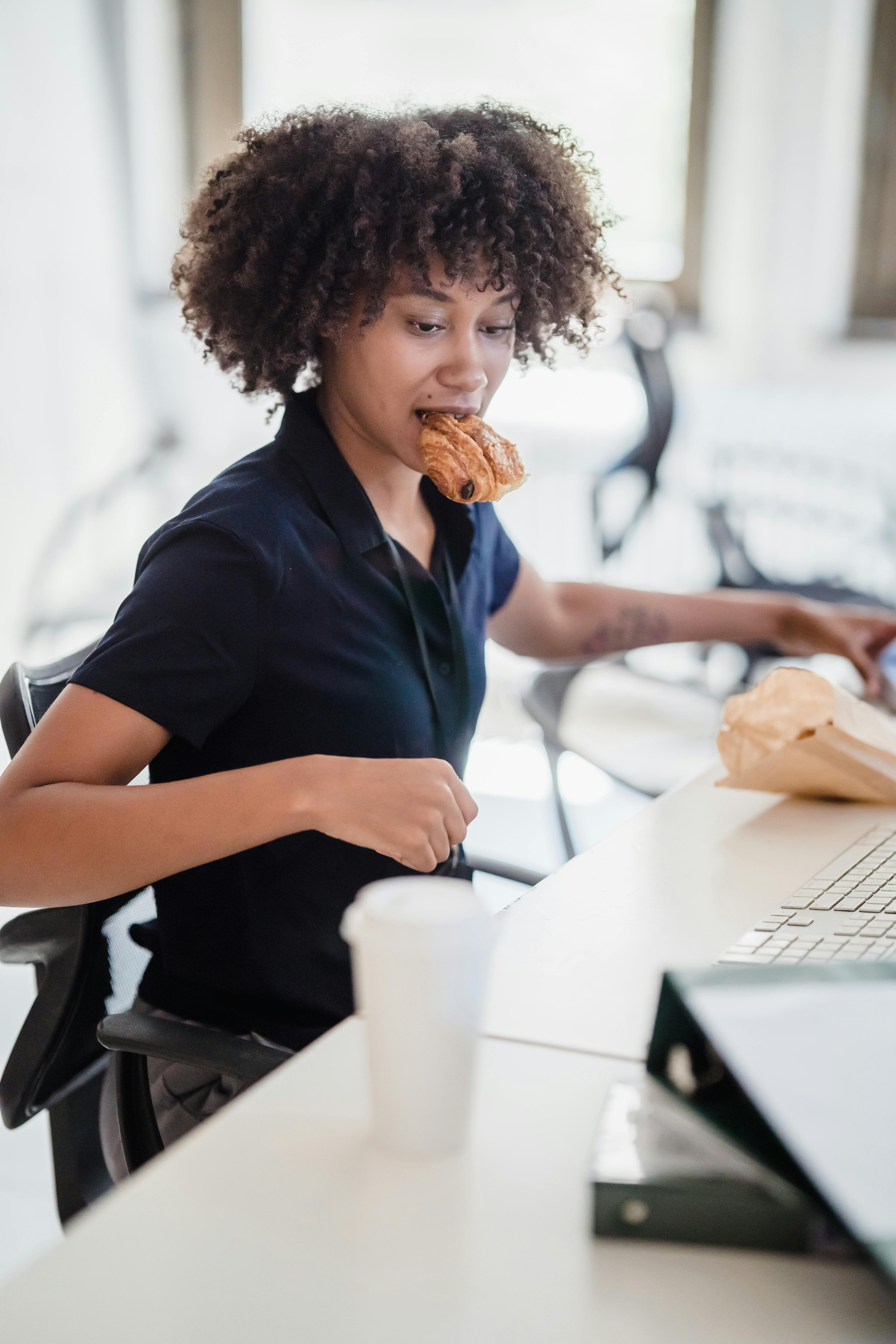 Woman Eating and Working in an Office · Free Stock Photo