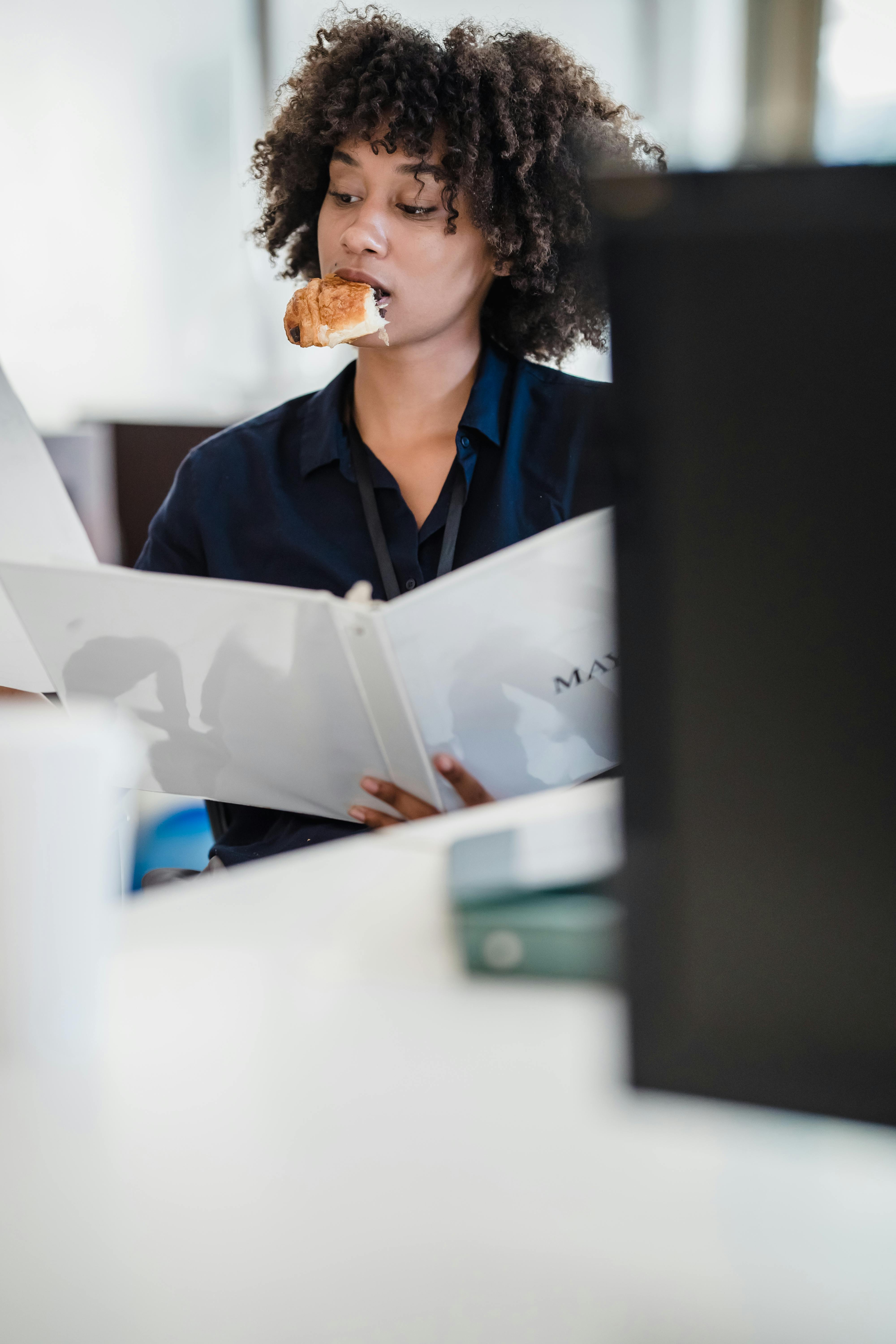Female Office Worker Eating while Working · Free Stock Photo