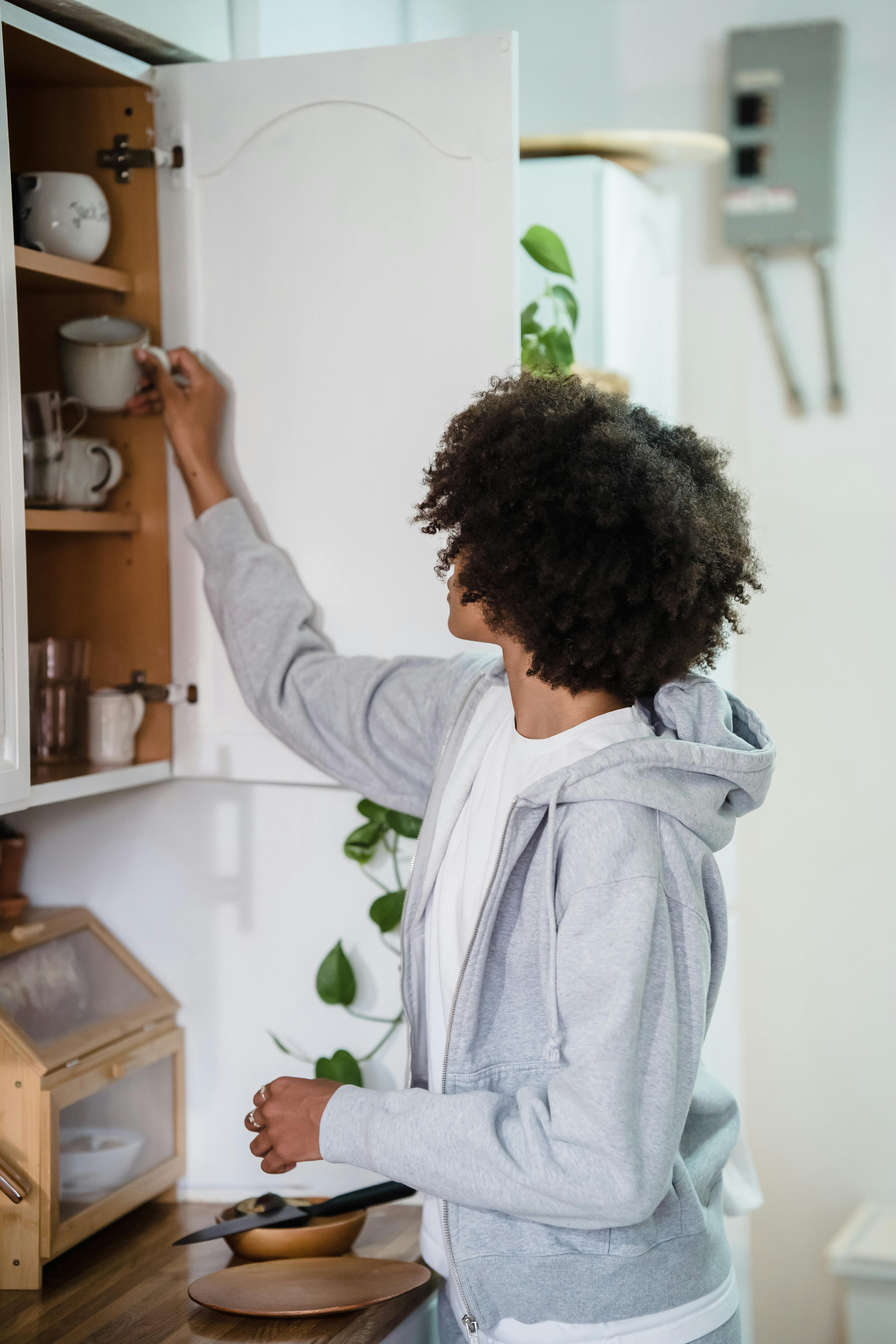 A Woman Taking a Cup from a Kitchen Cabinet · Free Stock Photo