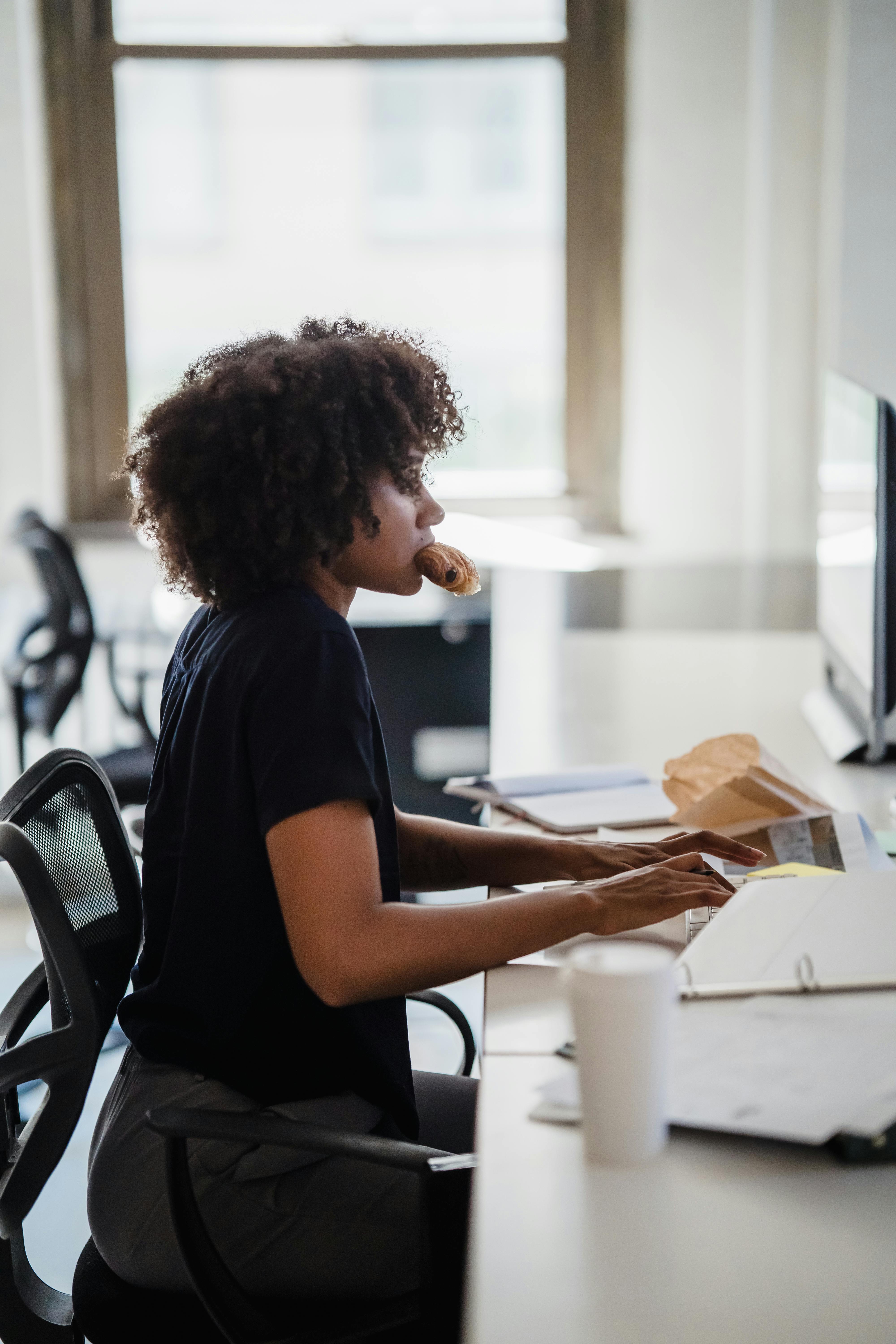 Woman Working on a Computer and Eating · Free Stock Photo
