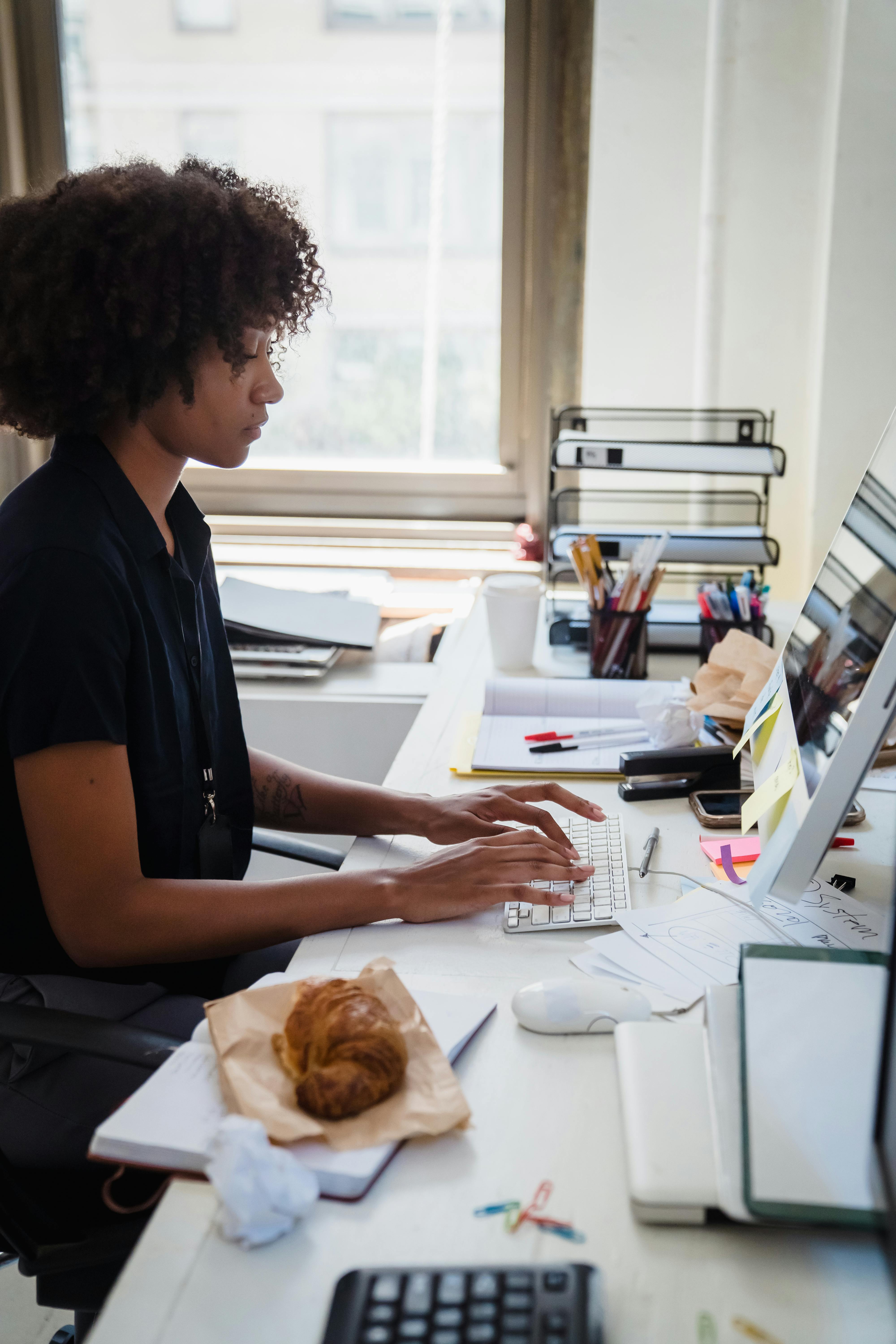 Woman Sitting by Desk Typing · Free Stock Photo