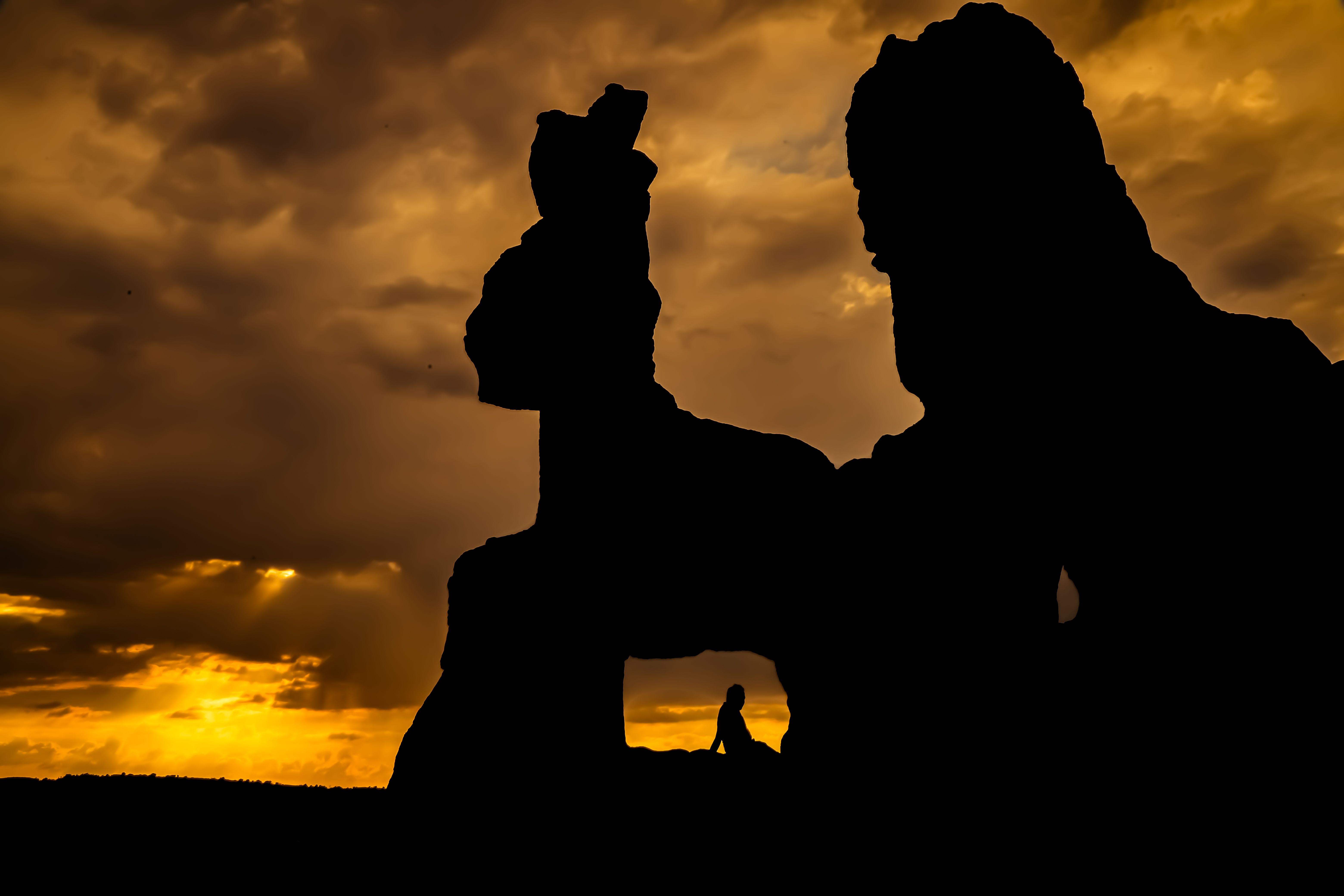 Silhouette of Man Sitting Under the Rock Formation · Free Stock Photo