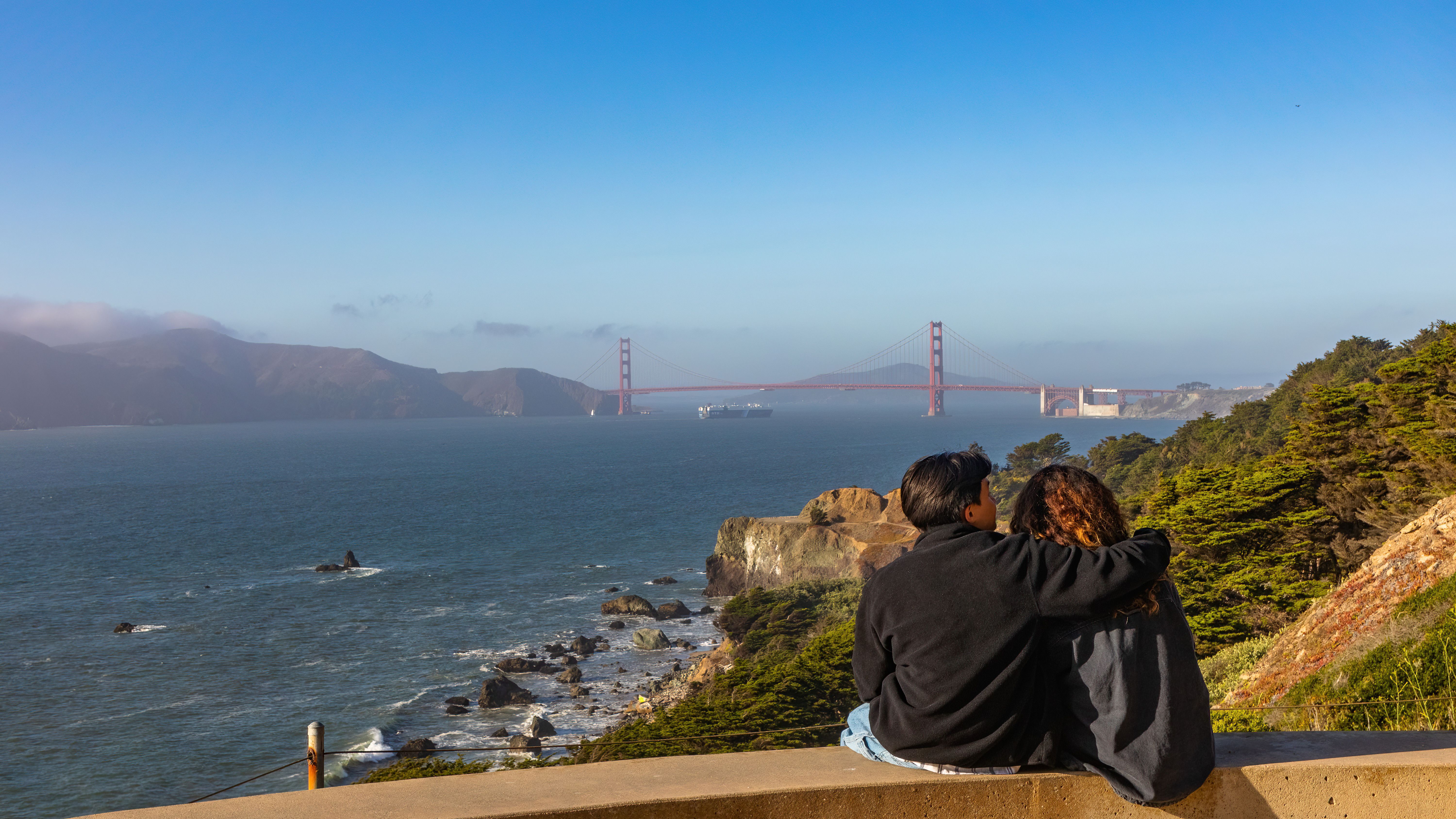 Couple Sitting on Ledge Overlooking San Francisco Bay · Free Stock Photo