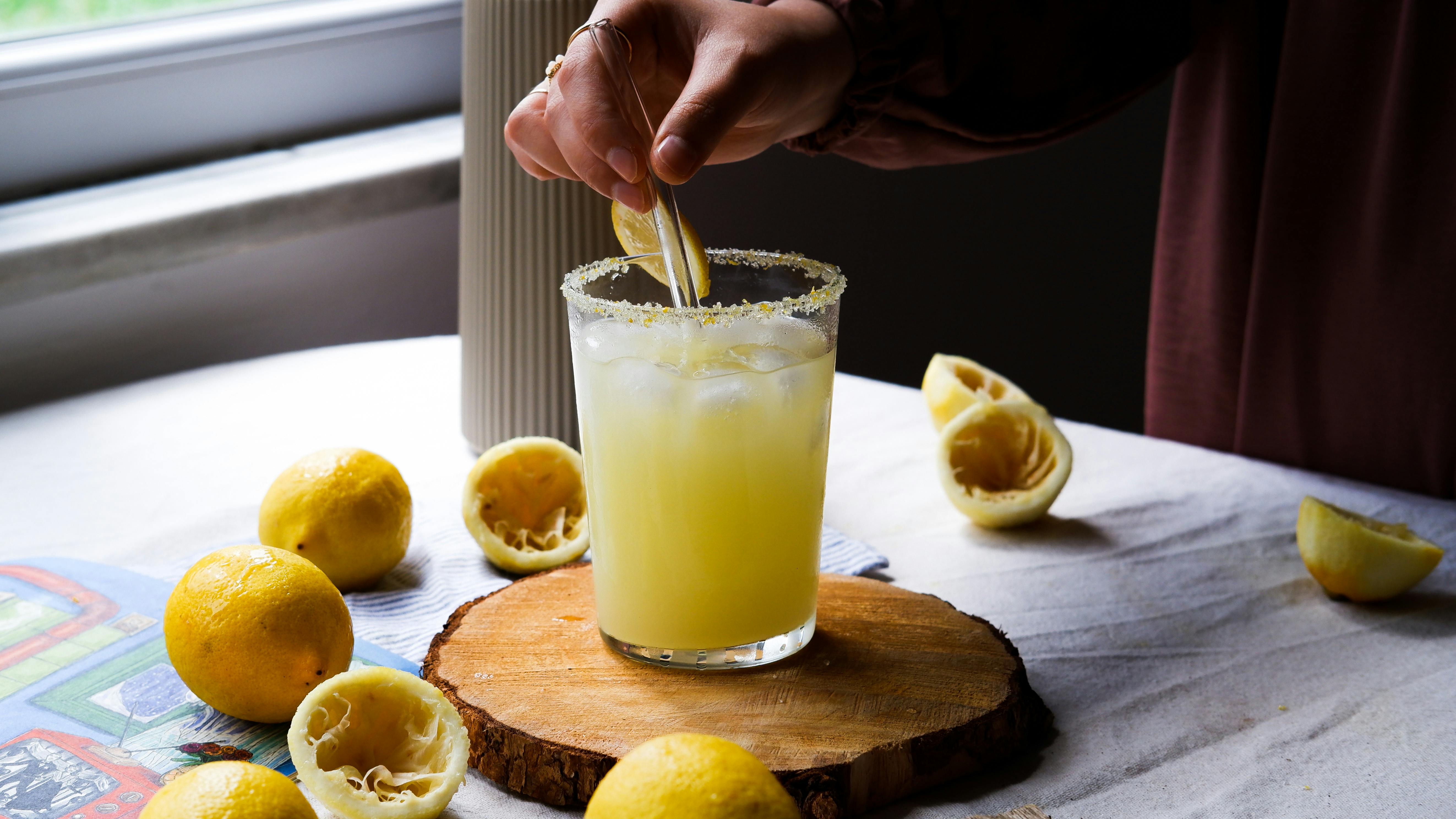 A Person Holding a Drinking Straw while Stirring on a Lemonade Juice ...