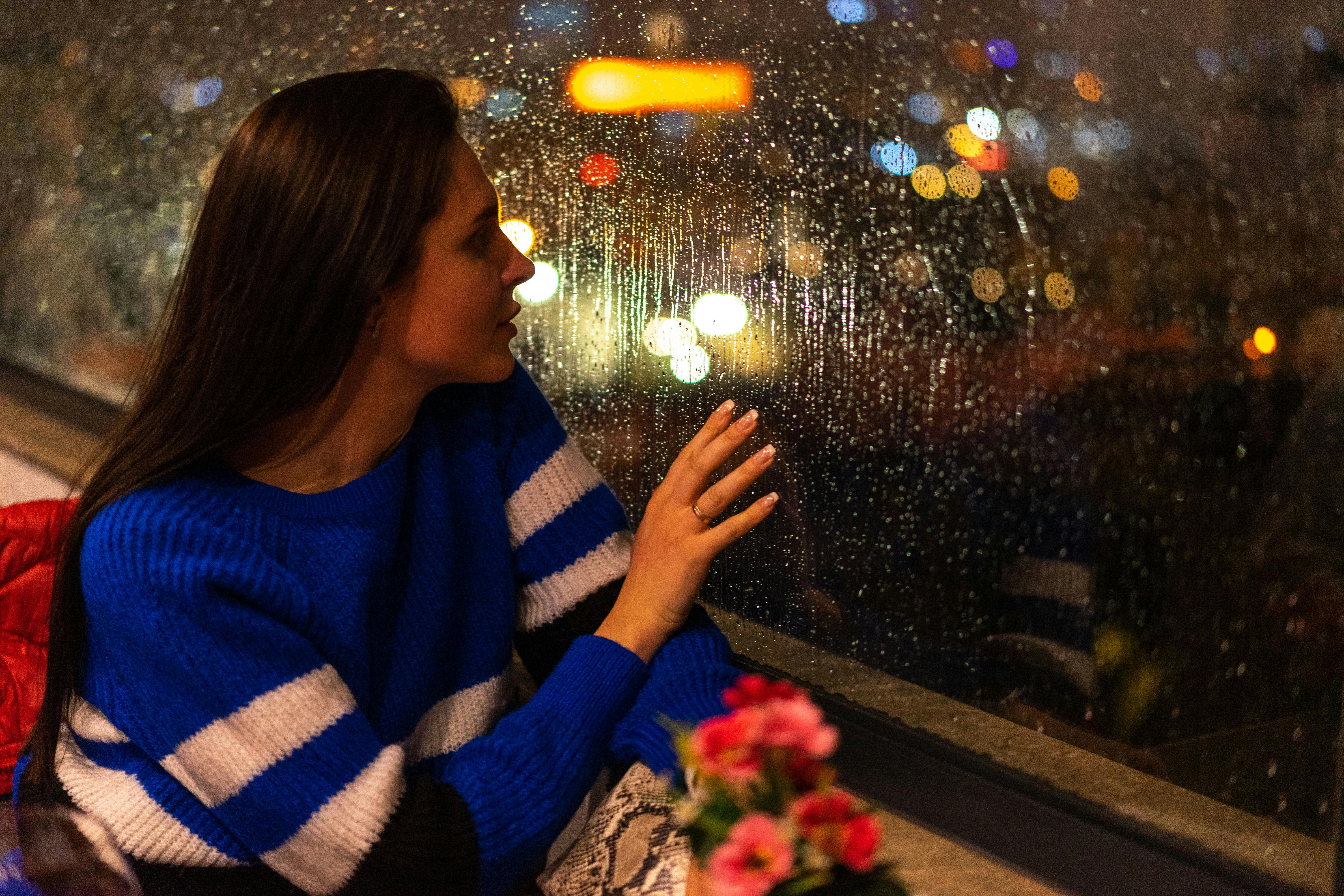 Brunette Looking Through Window on Rainy Night · Free Stock Photo