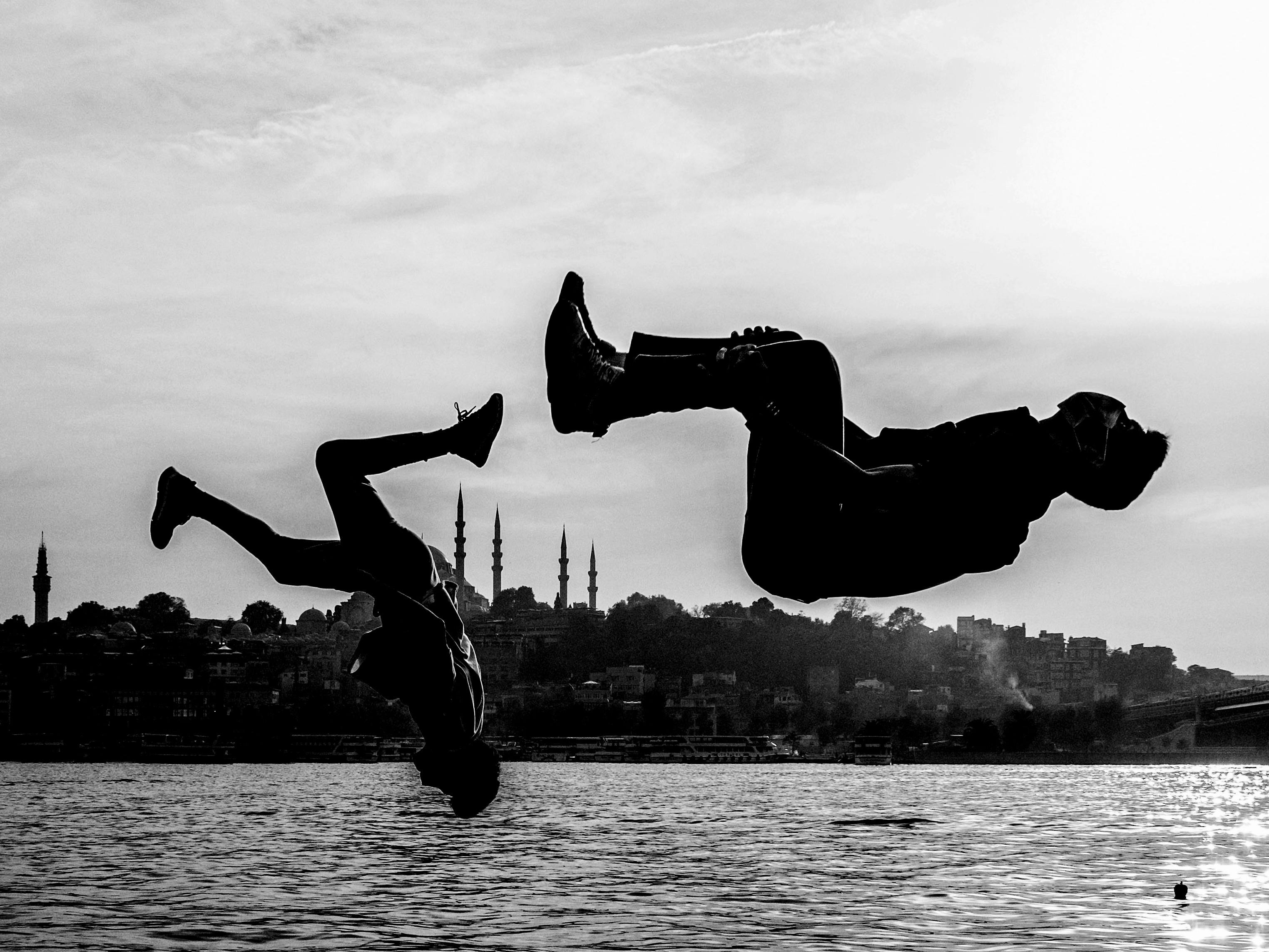 Grayscale Photo of Men Tumbling Near Body of Water · Free Stock Photo