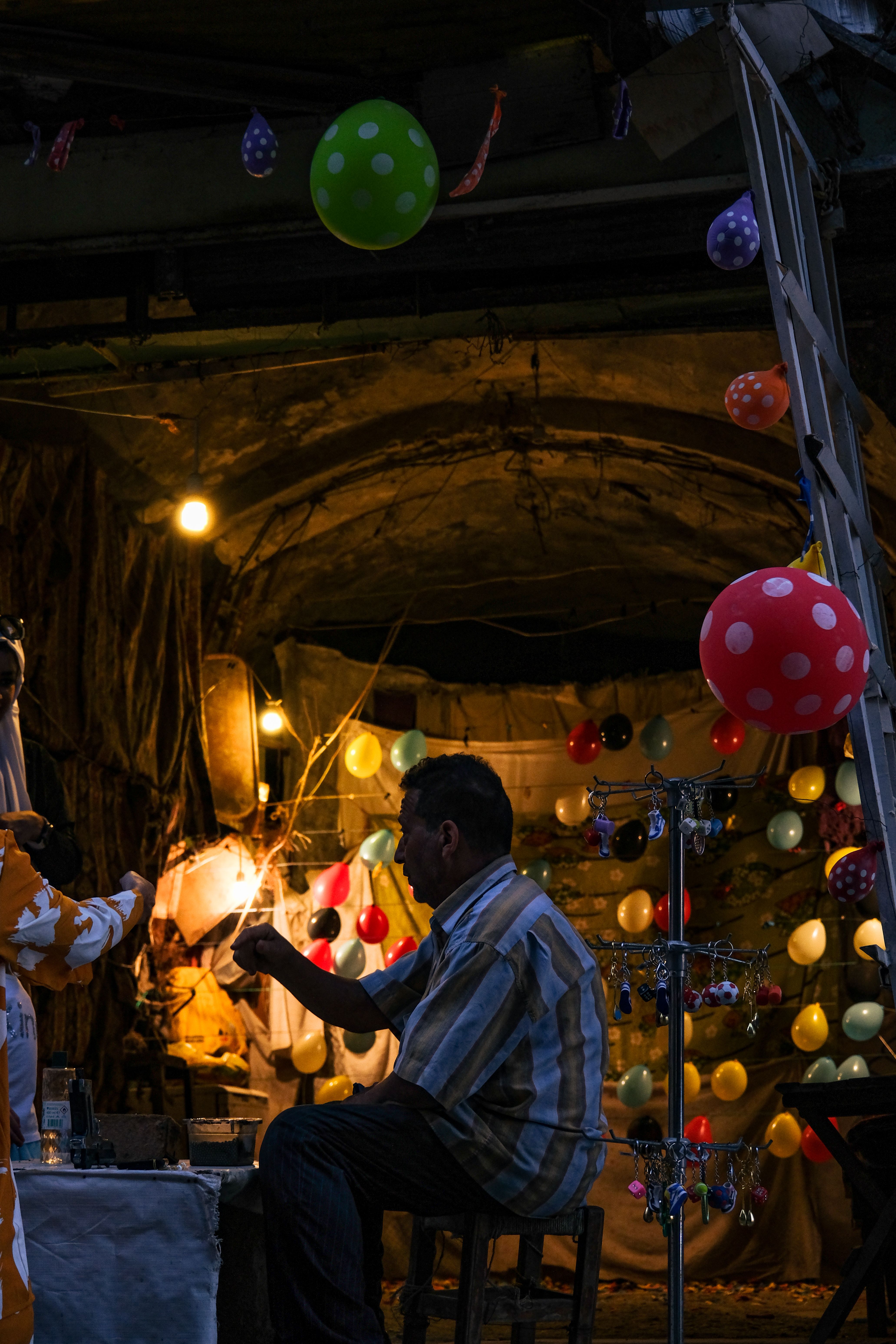 Man Selling Balloons by an Illuminated Arch · Free Stock Photo