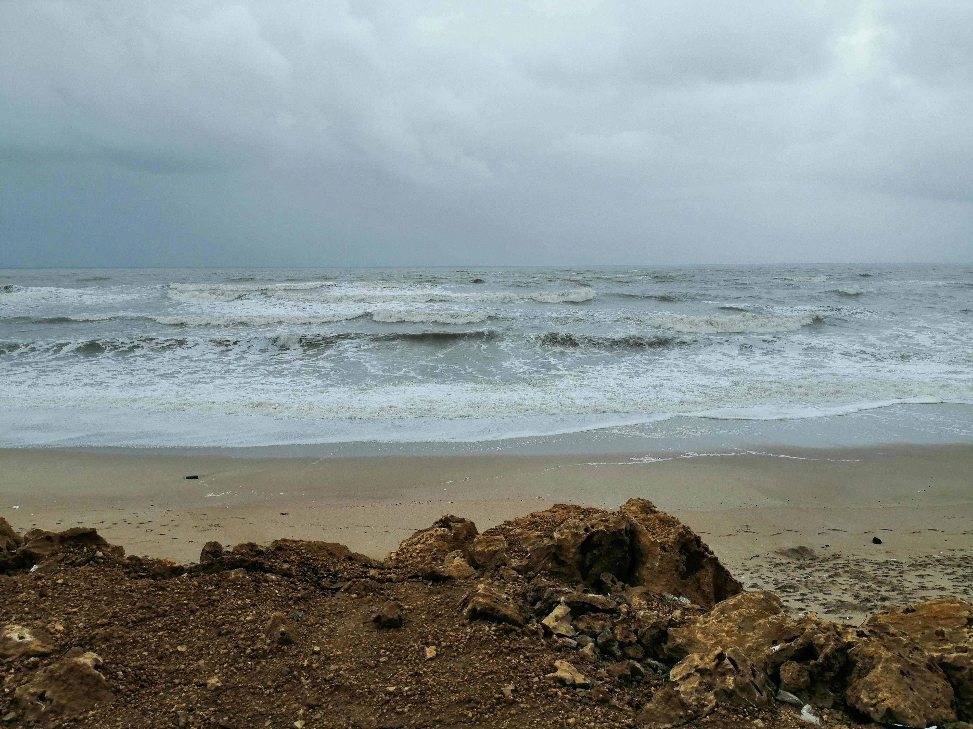 Brown Rocky Shore Near Body of Water Under White Cloudy Sky · Free ...