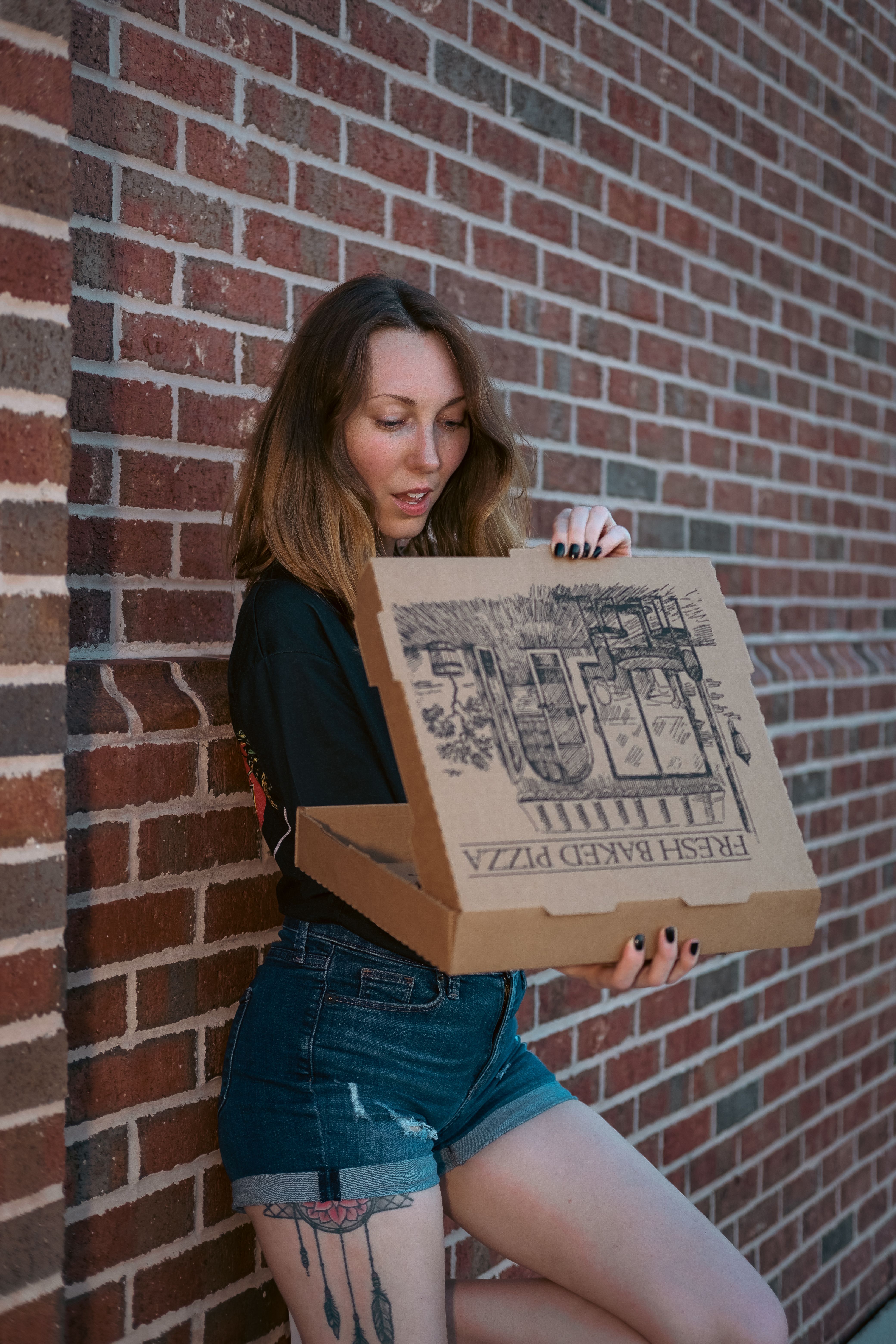 Woman Holding a Pizza Box in Front of Brick Wall · Free Stock Photo
