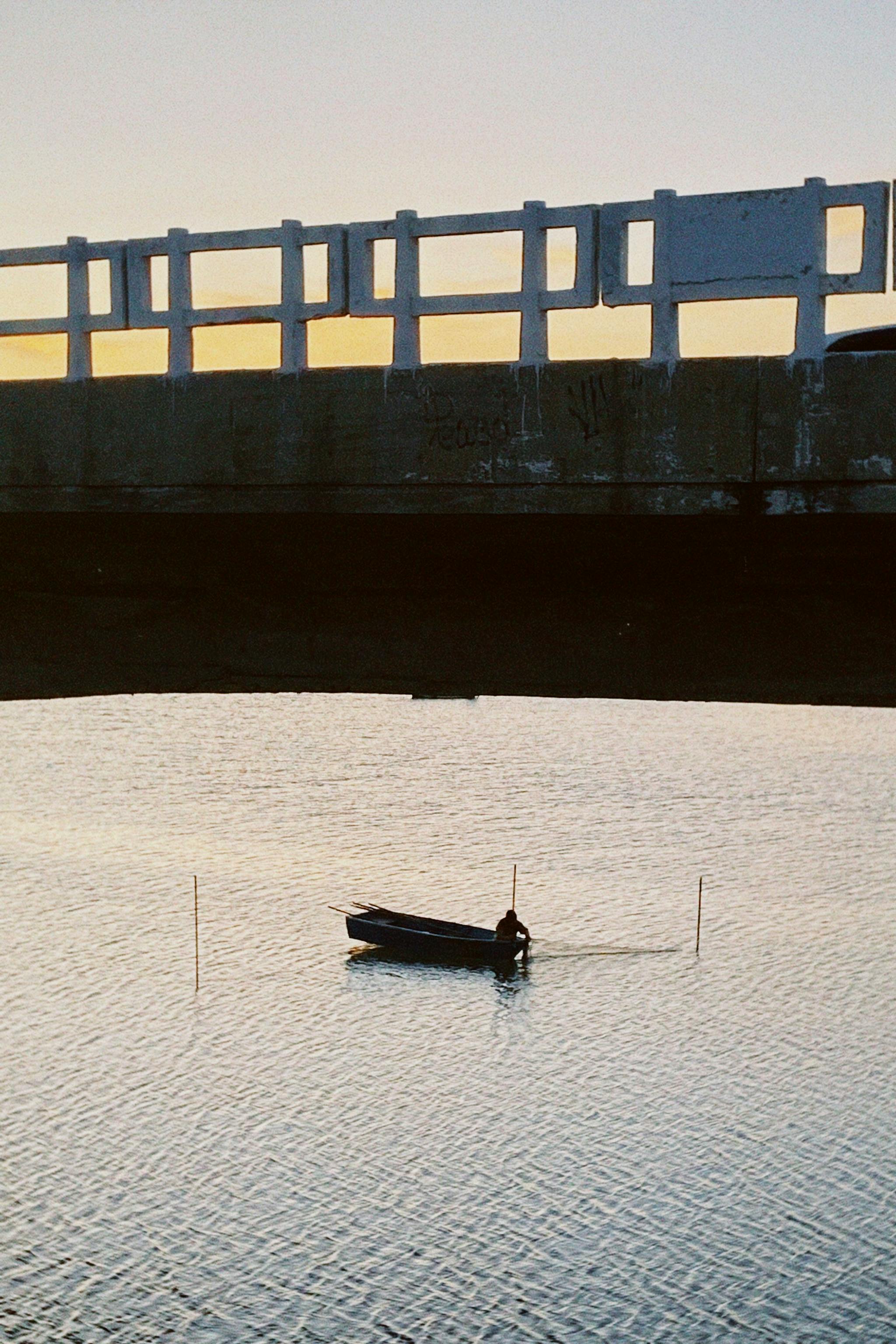 Person on Sailing Boat Under a Concrete Bridge · Free Stock Photo