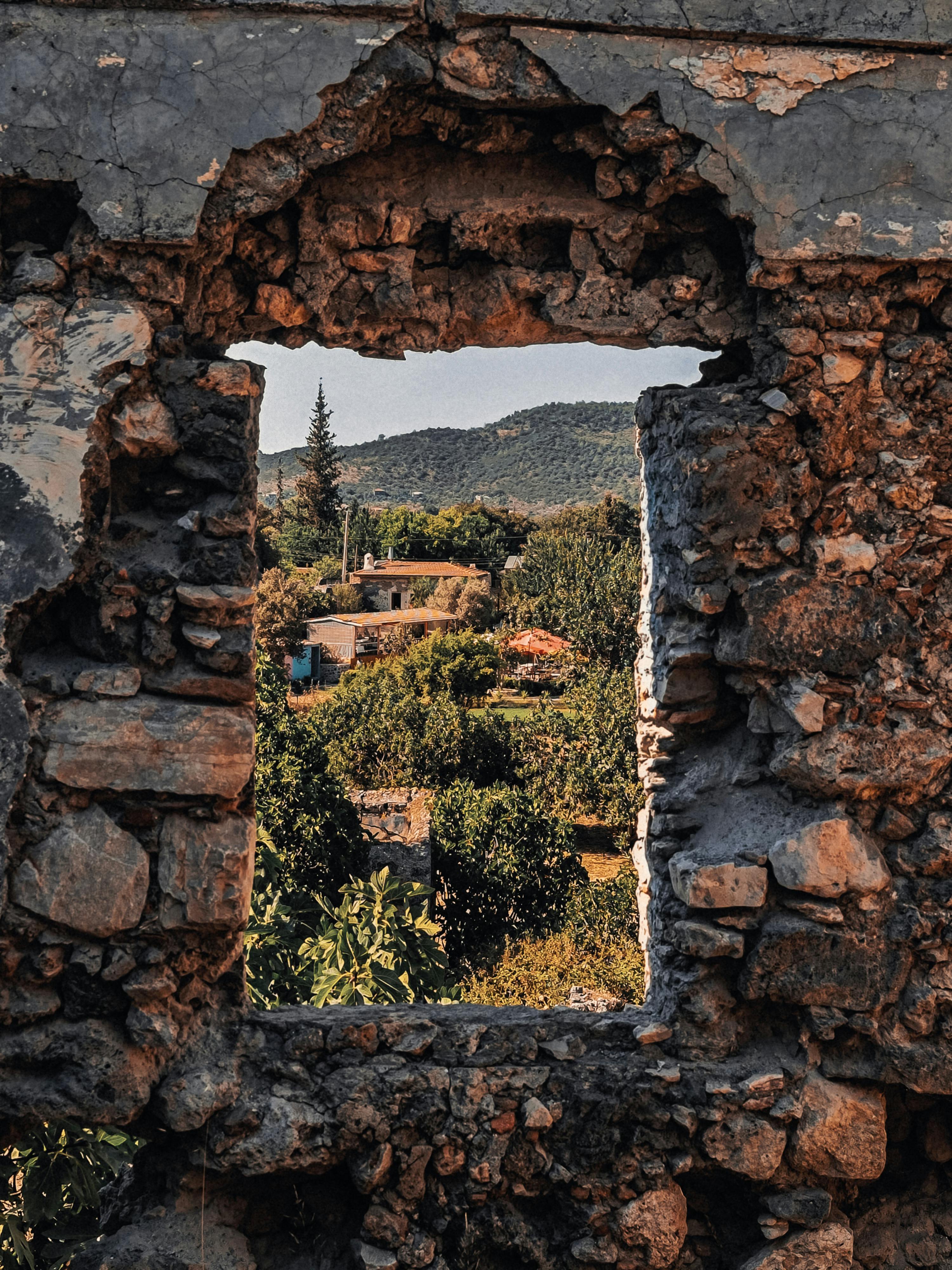 View of Houses Near Mountain From Stone Wall with Window · Free Stock Photo
